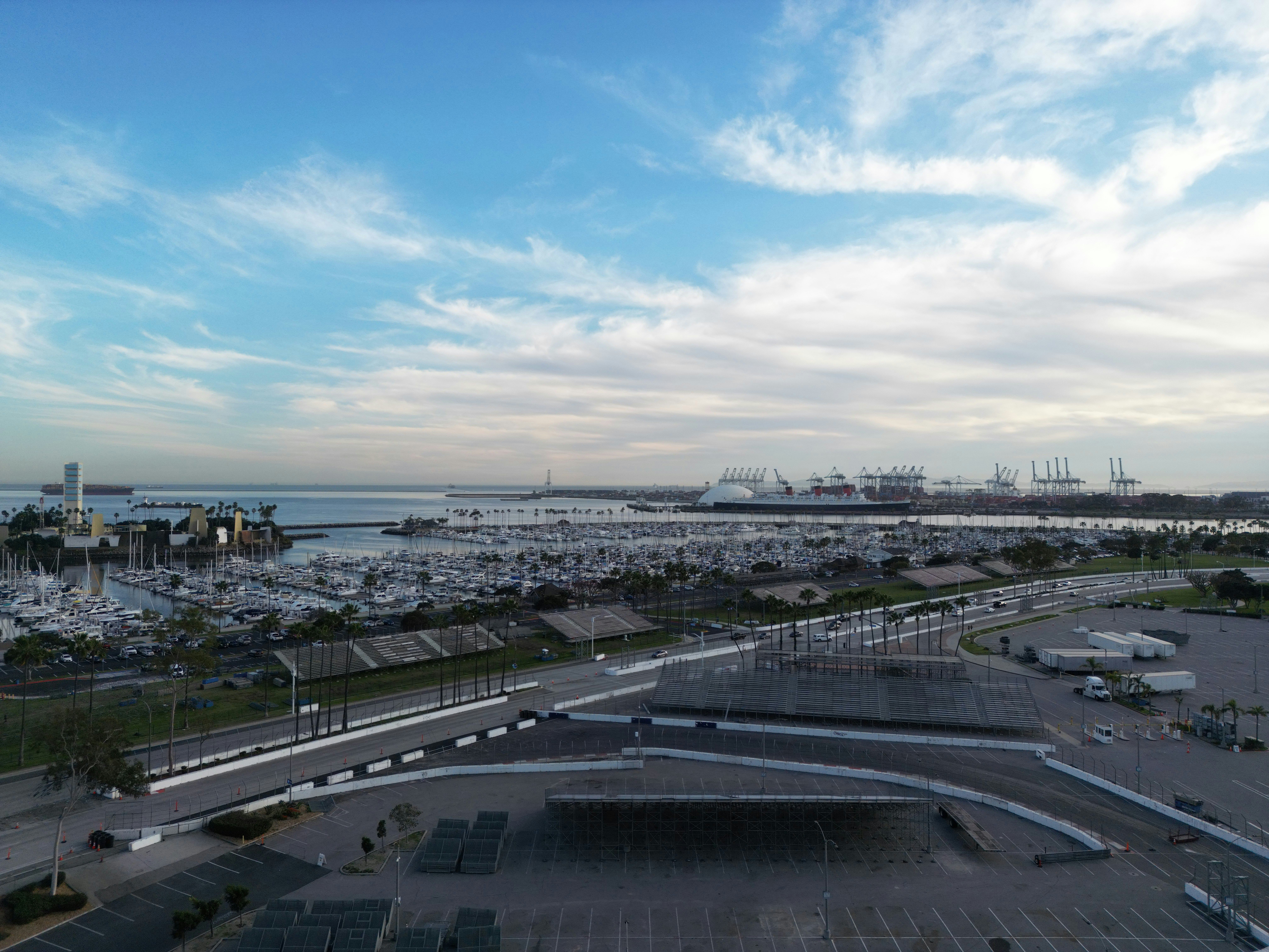 Harbor filled with boats against a backdrop of industrial cranes and a cloudy sky.