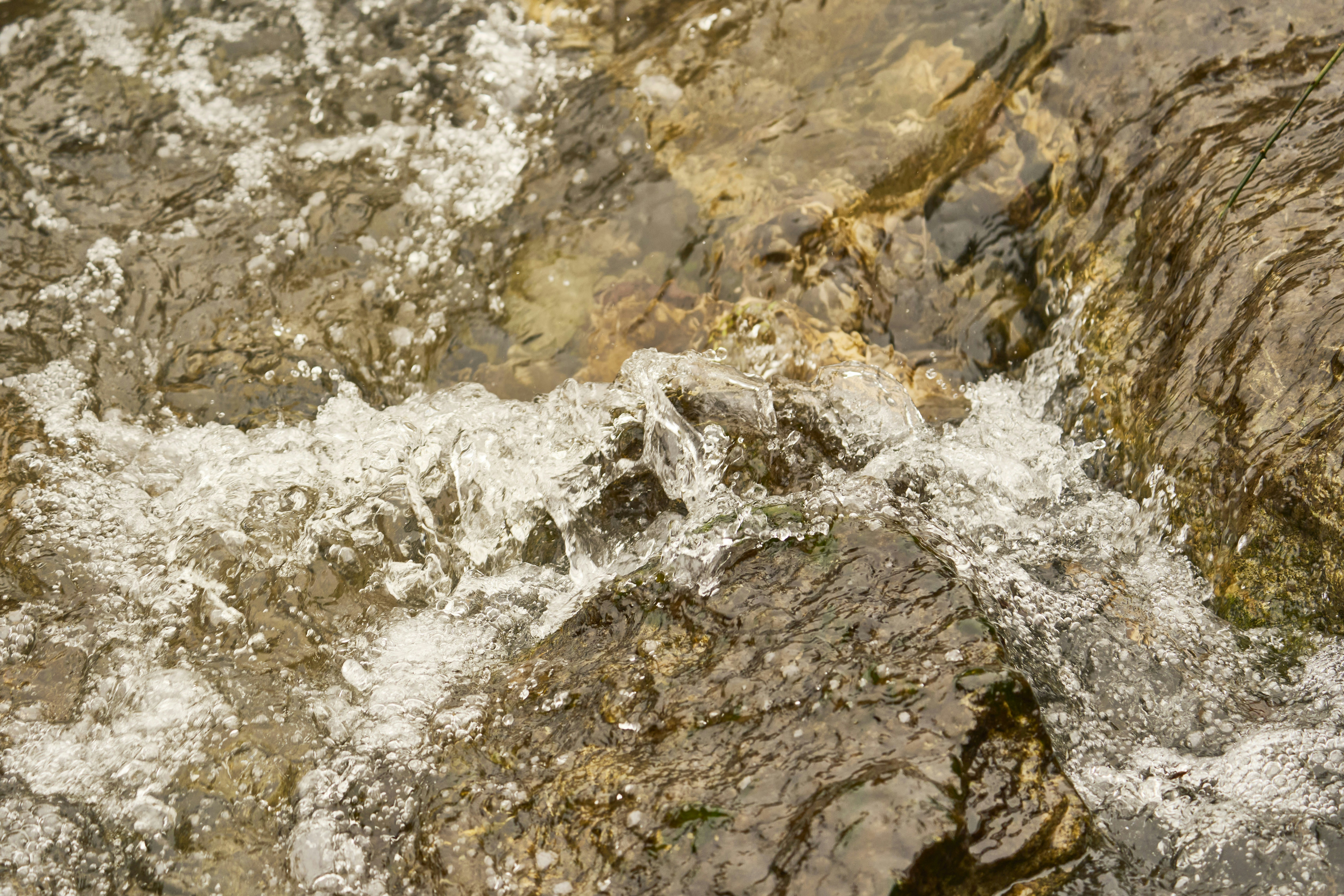 Water flowing over textured rocks in a natural stream.