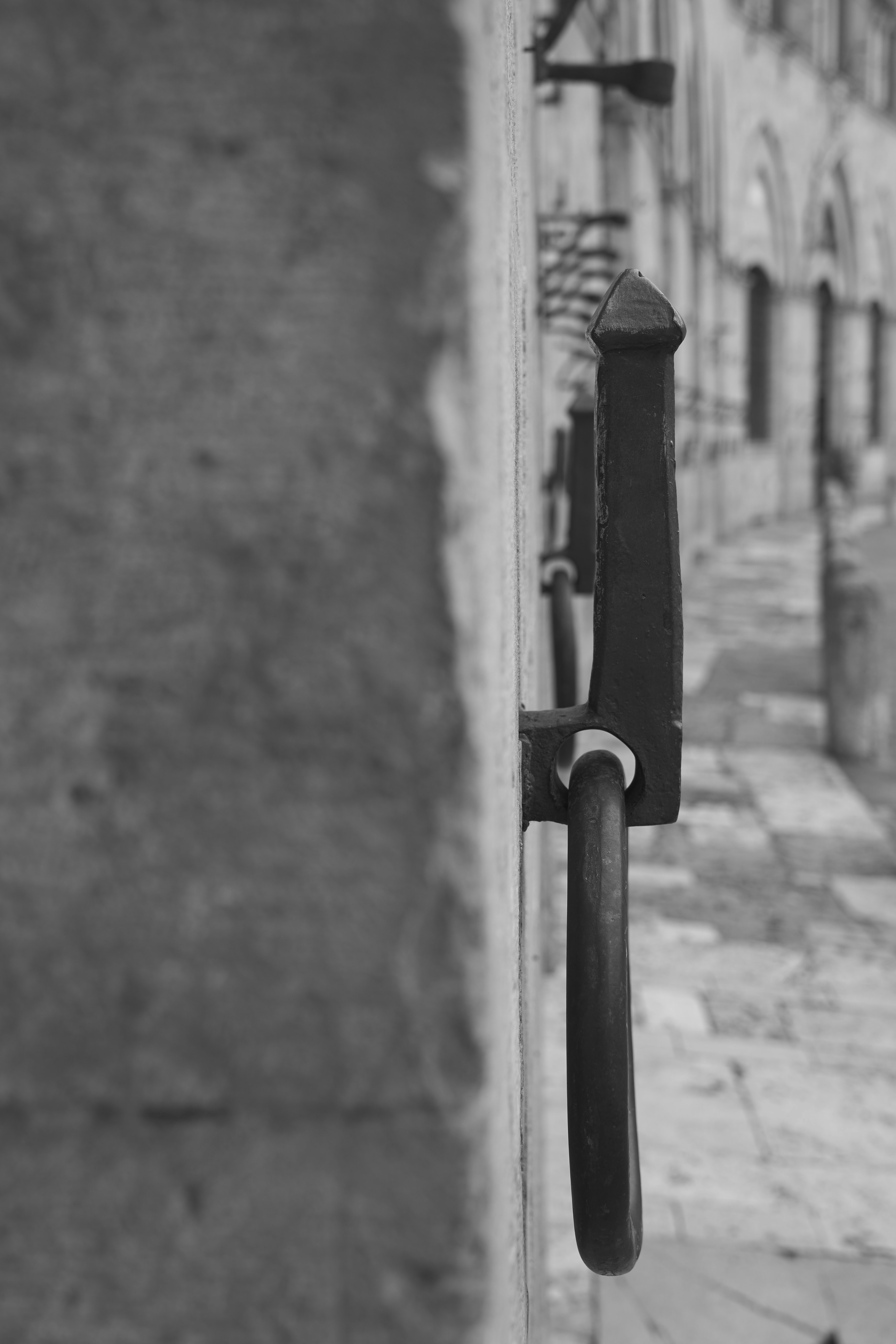 Iron Line in a Narrow Street: A Sharp Foreground Handrail Against Blurred Arches