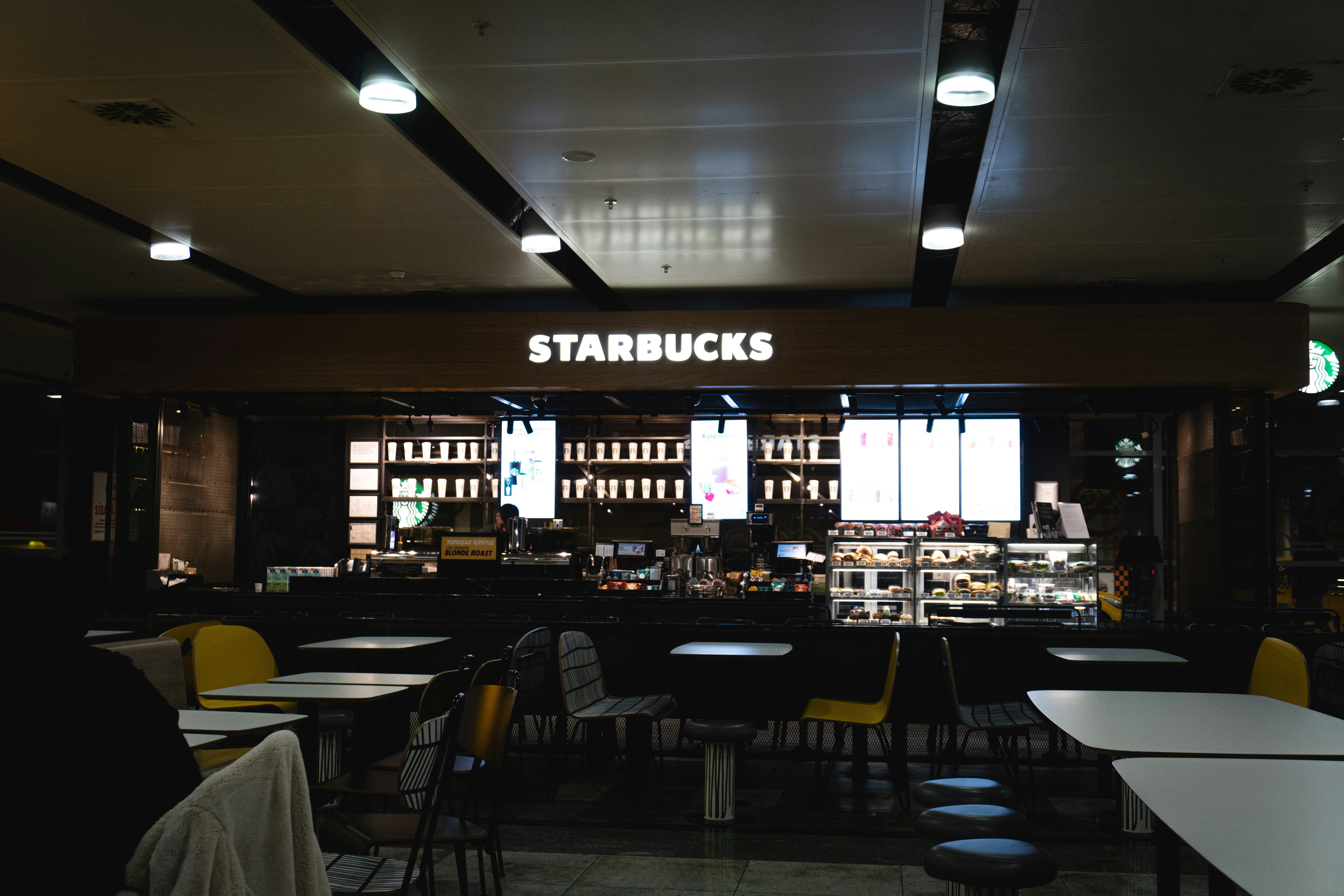 Dimly lit Starbucks counter with illuminated menu boards and empty seating area.
