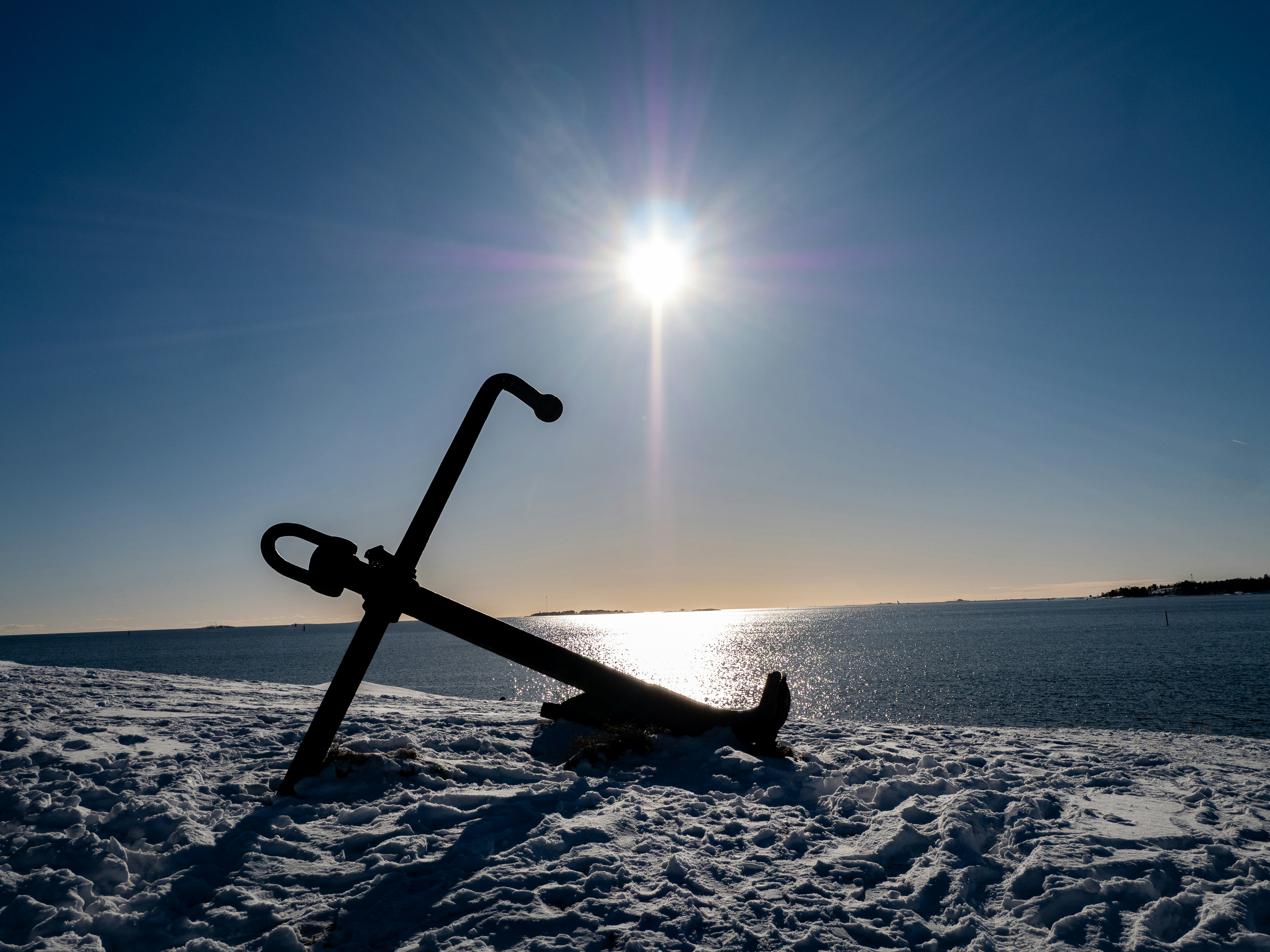 Sunlit Sliver of Shore: Debris and Dune under a Bright Arctic Sky