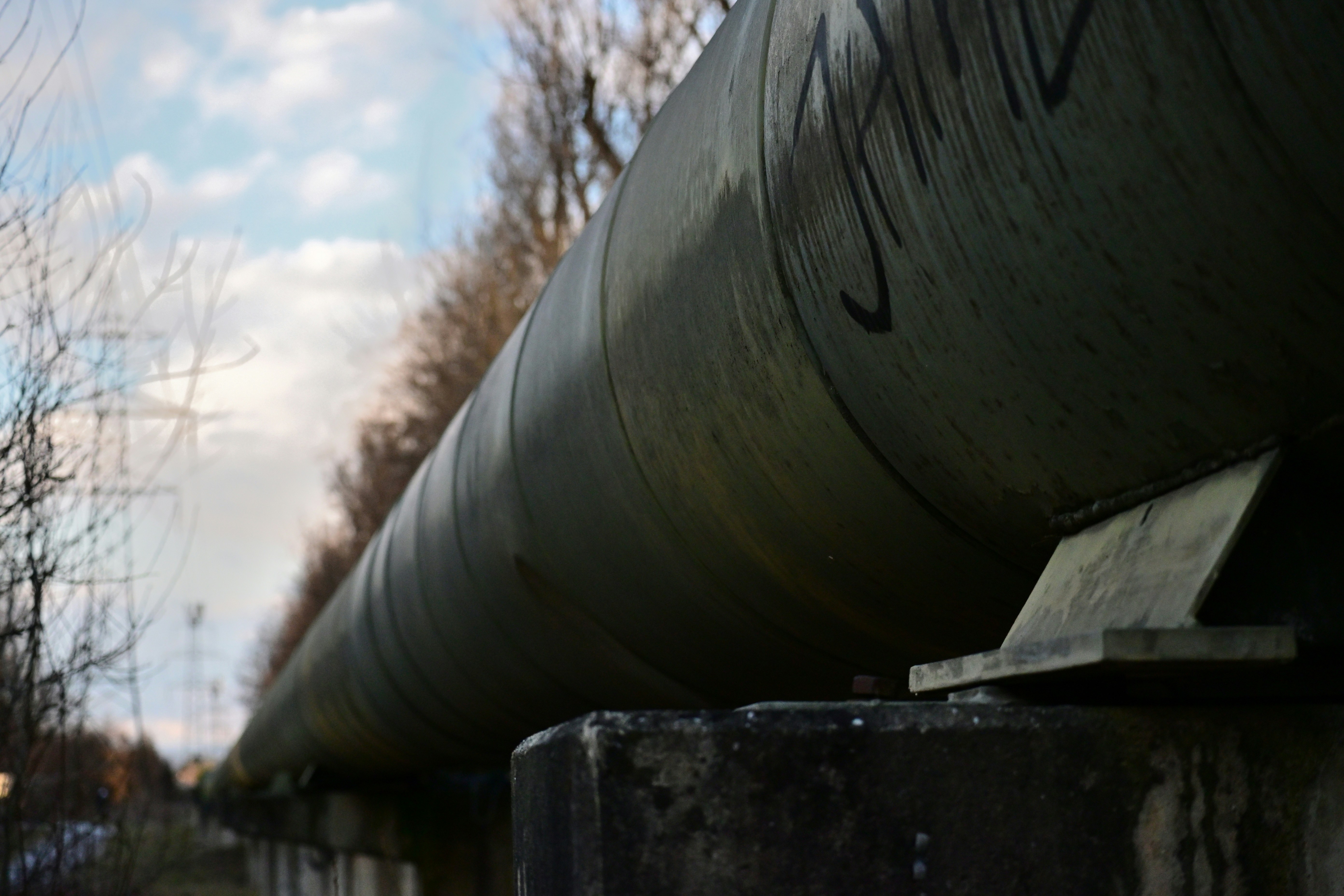 Large green pipeline stretching into the distance beneath a cloudy sky.