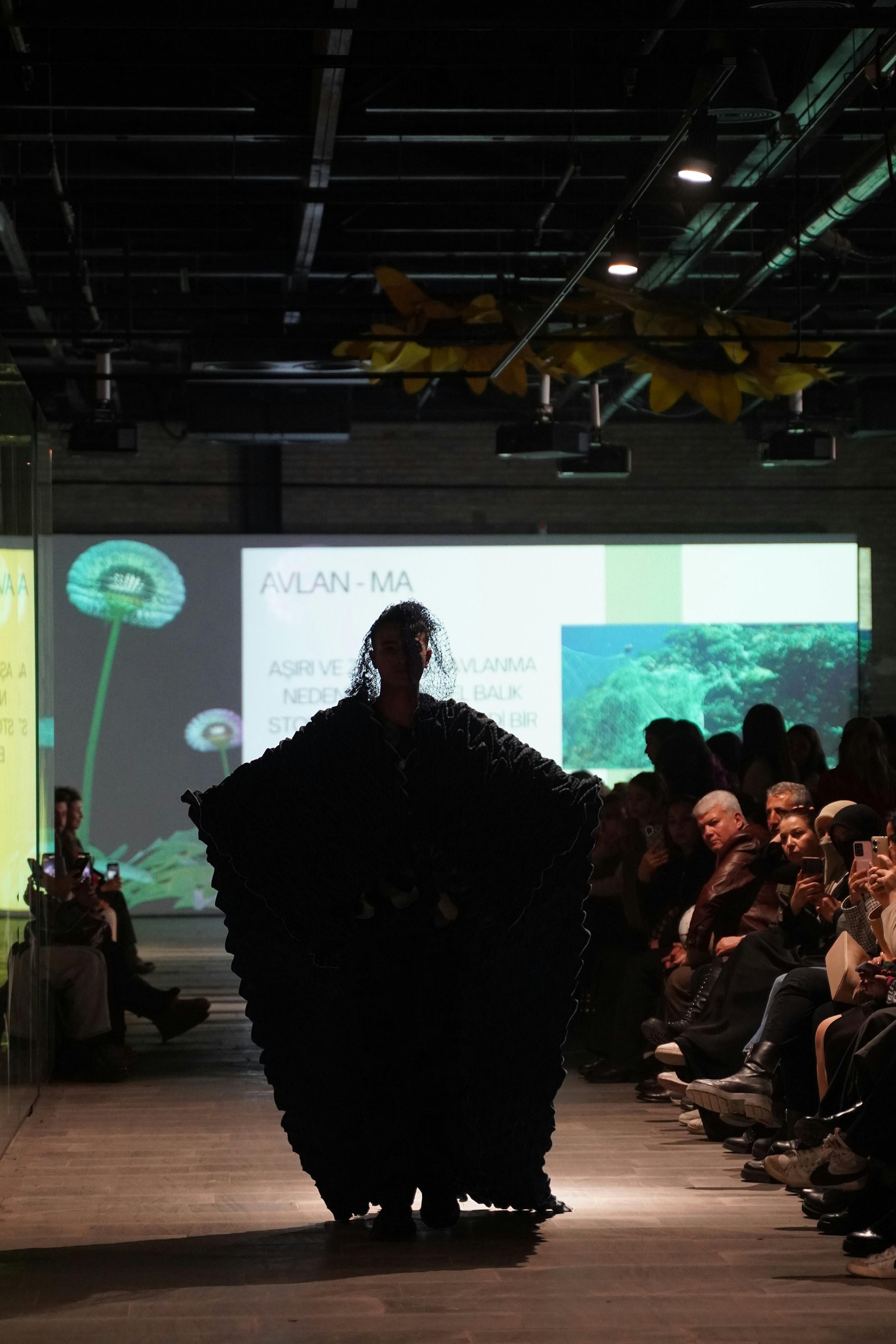 Silhouette on the Runway: Dark Cloak Meets Neon Stage