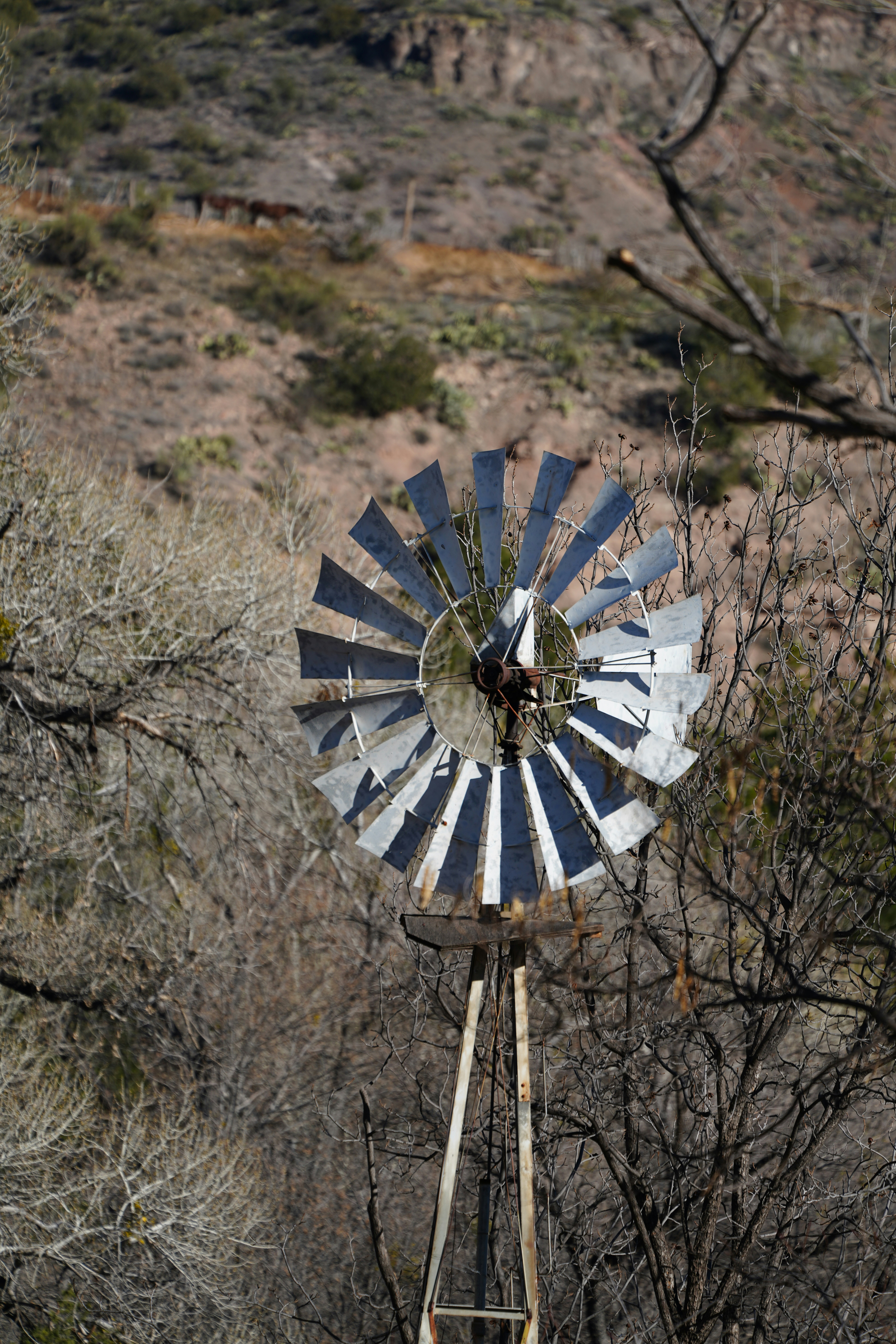 A windmill stands tall in a desert landscape.