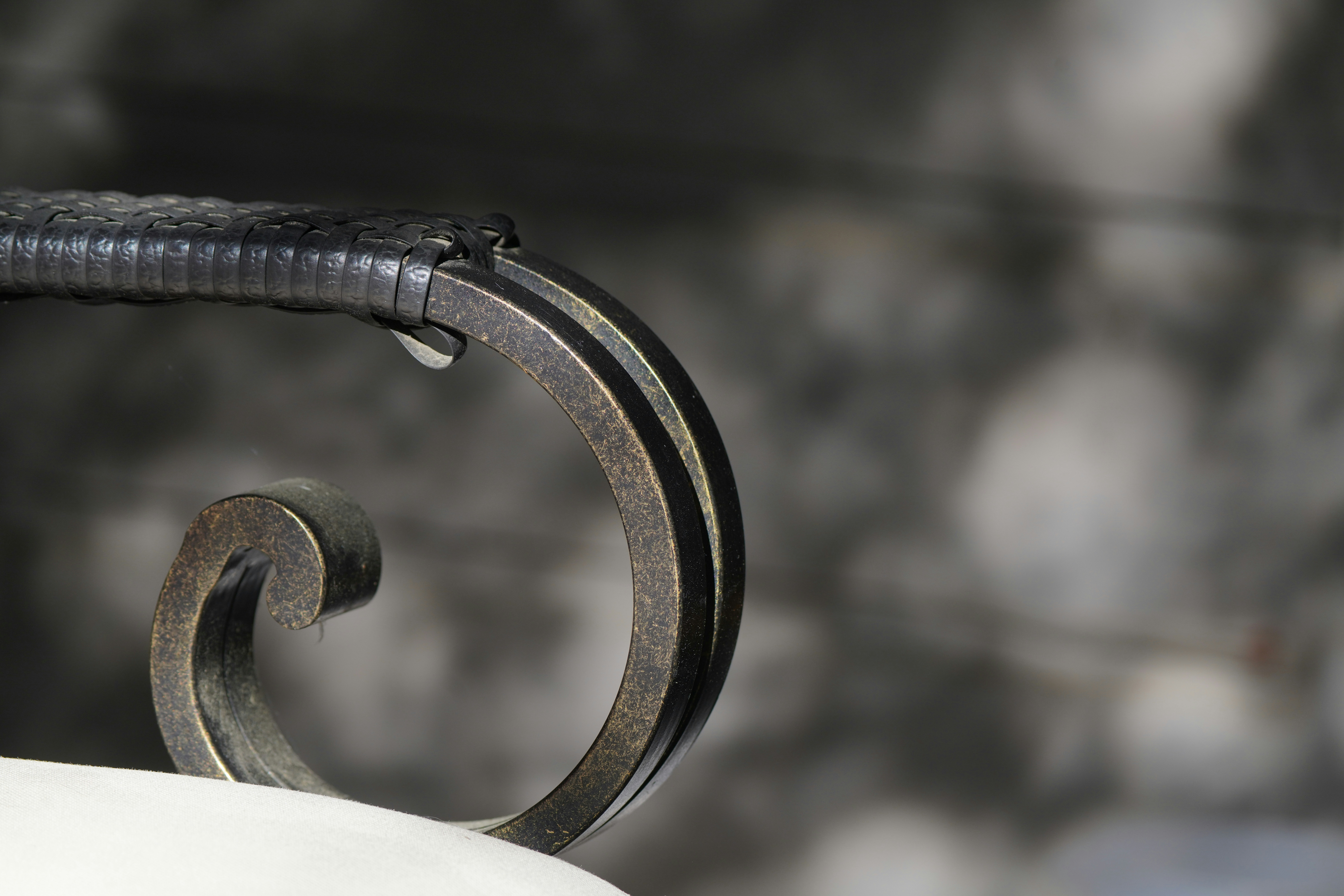 Close-up of a weathered metal scroll against a soft bokeh background.
