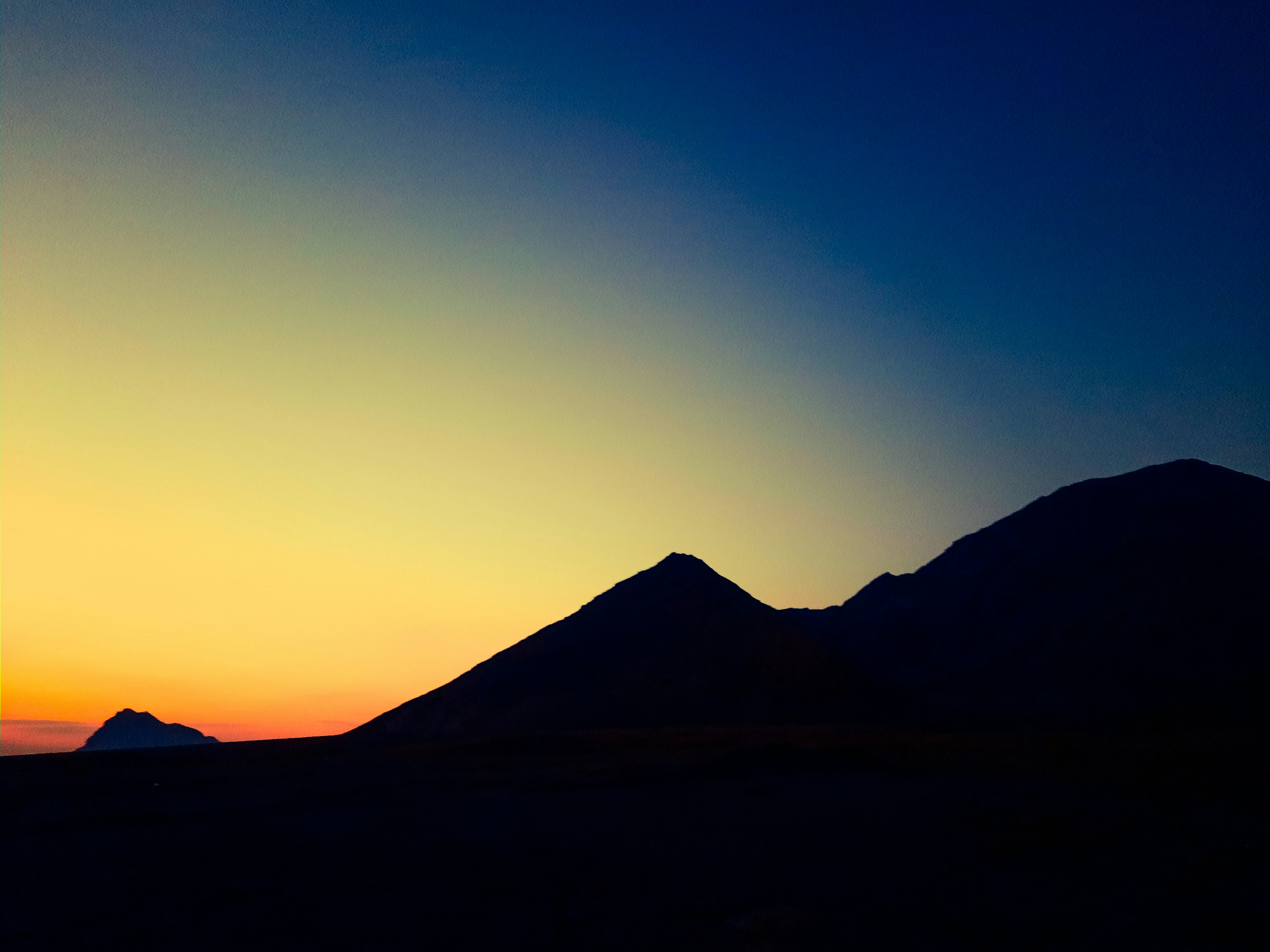 Silhouetted mountains against a gradient sky during sunset in a desert landscape.