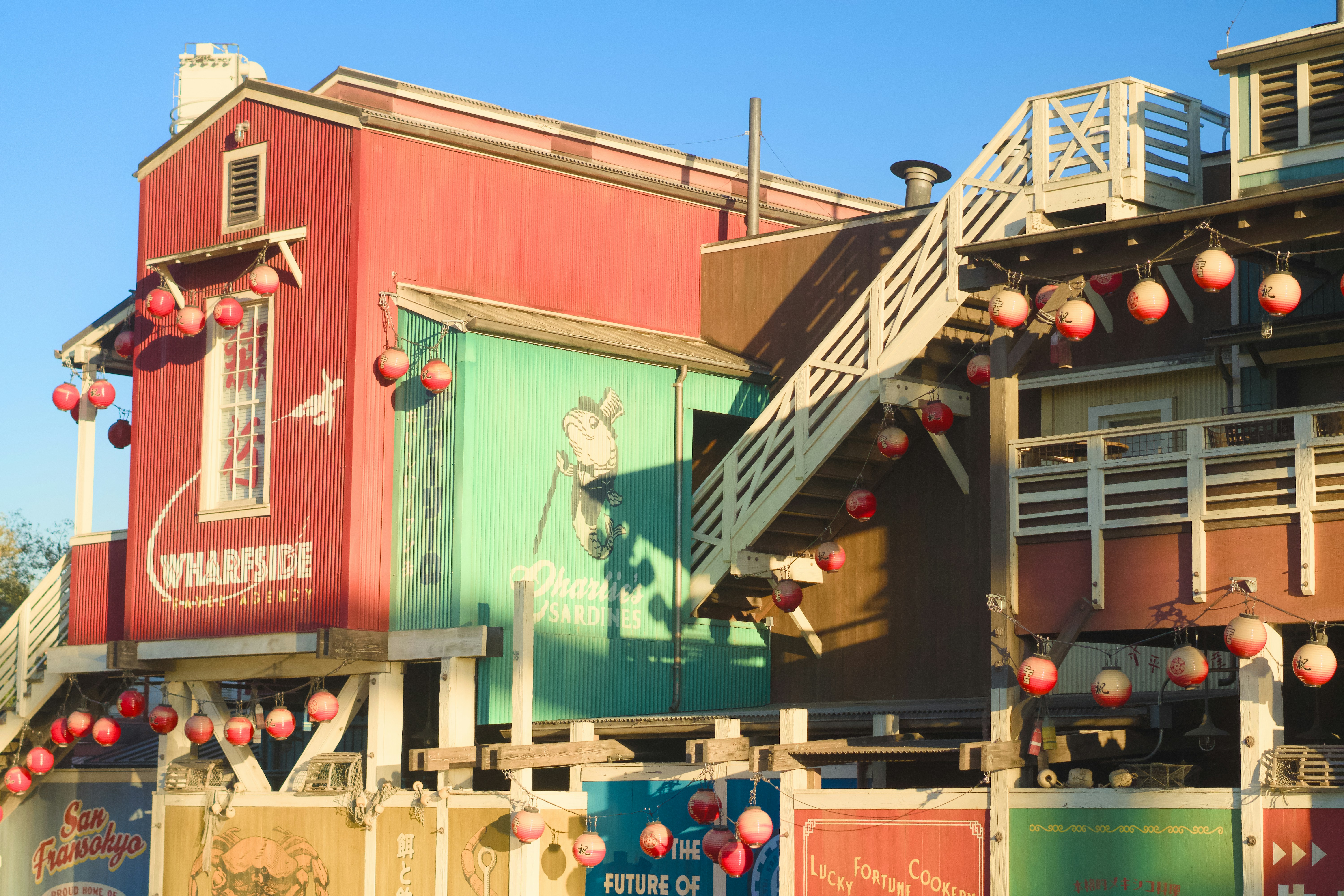 Colorful building adorned with red lanterns and vintage signs under clear blue sky.