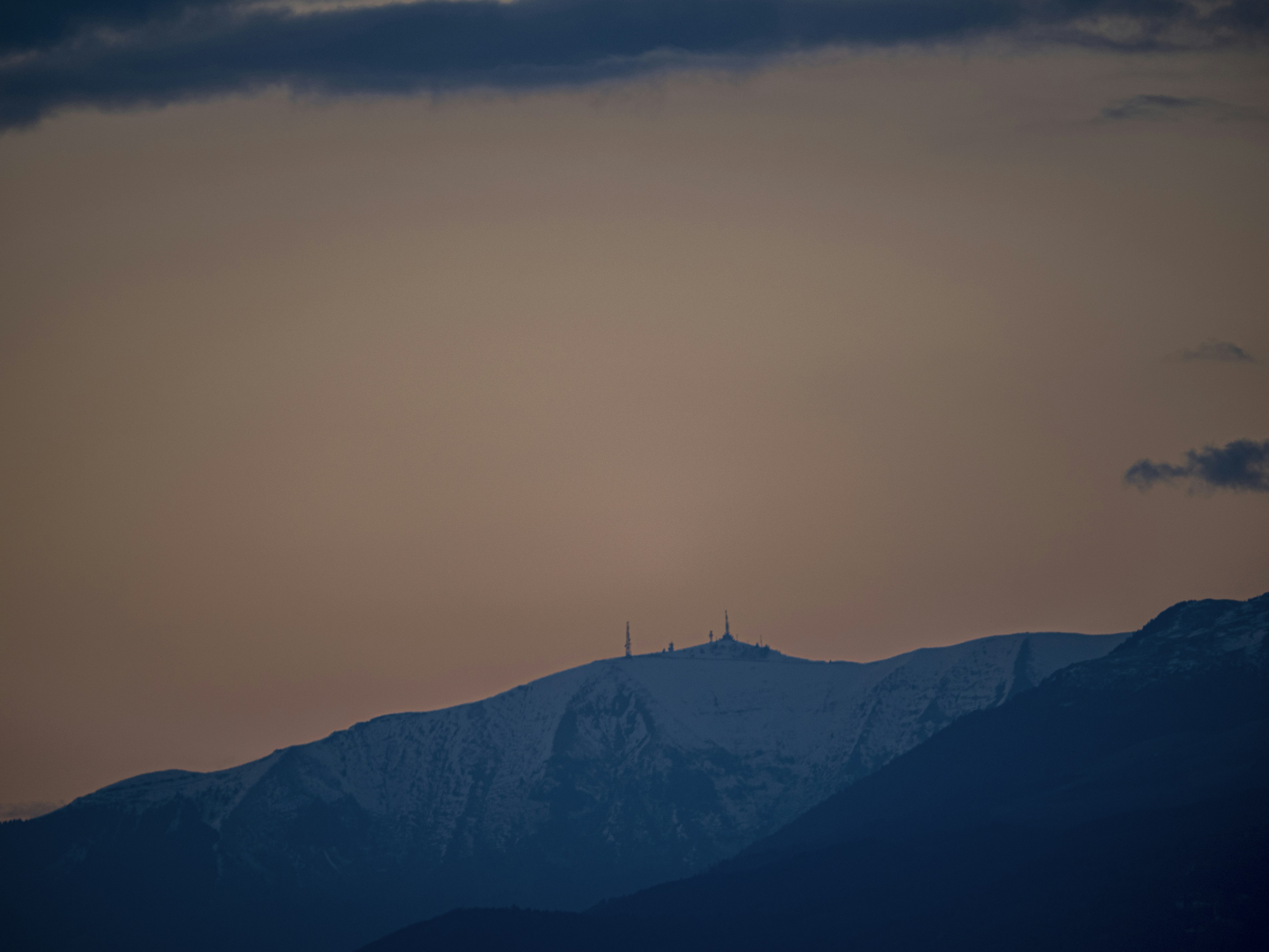 Distant mountain range with snow-capped peaks under a dusky sky.
