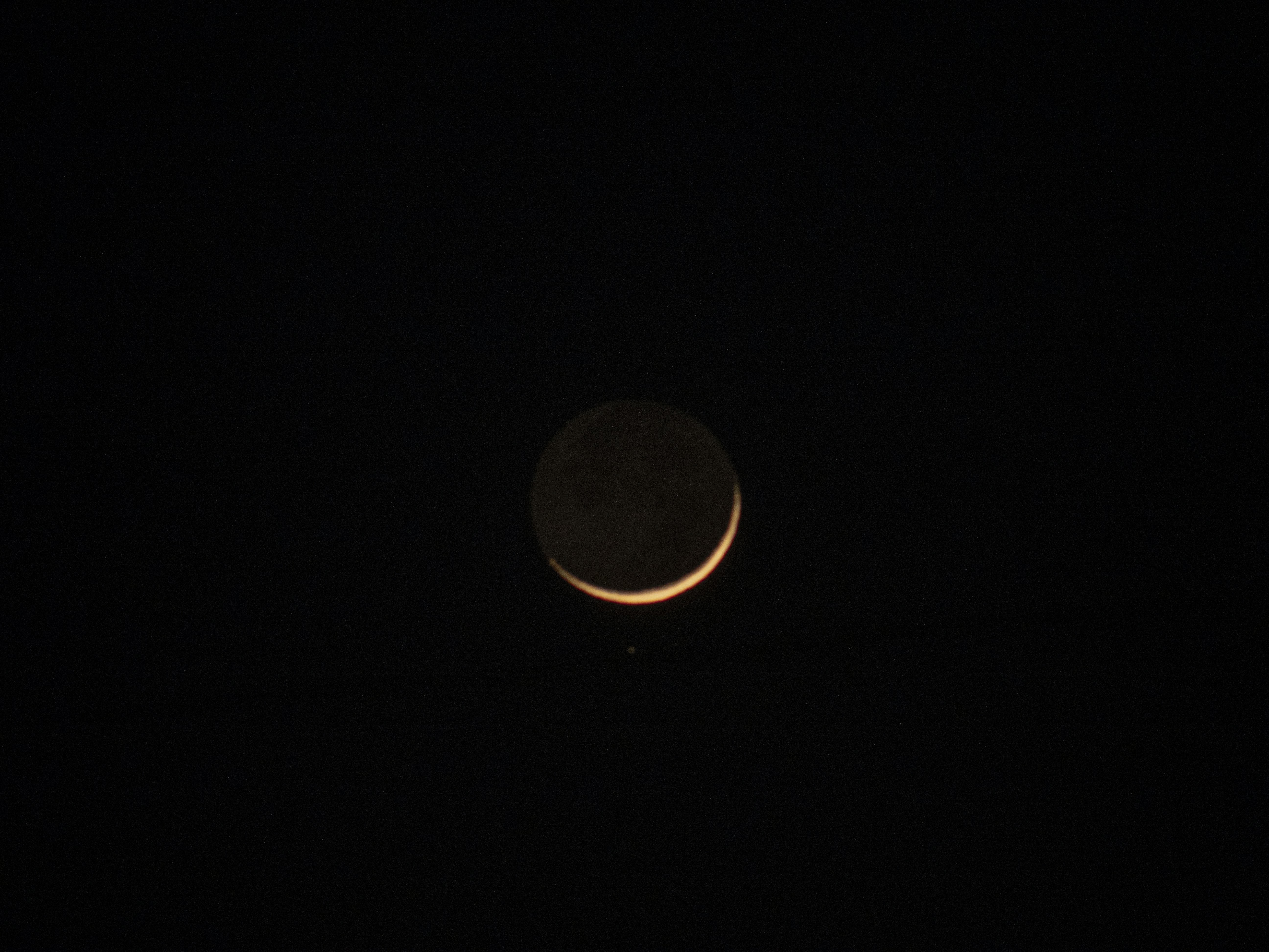 Thin crescent moon against a pitch-black night sky.
