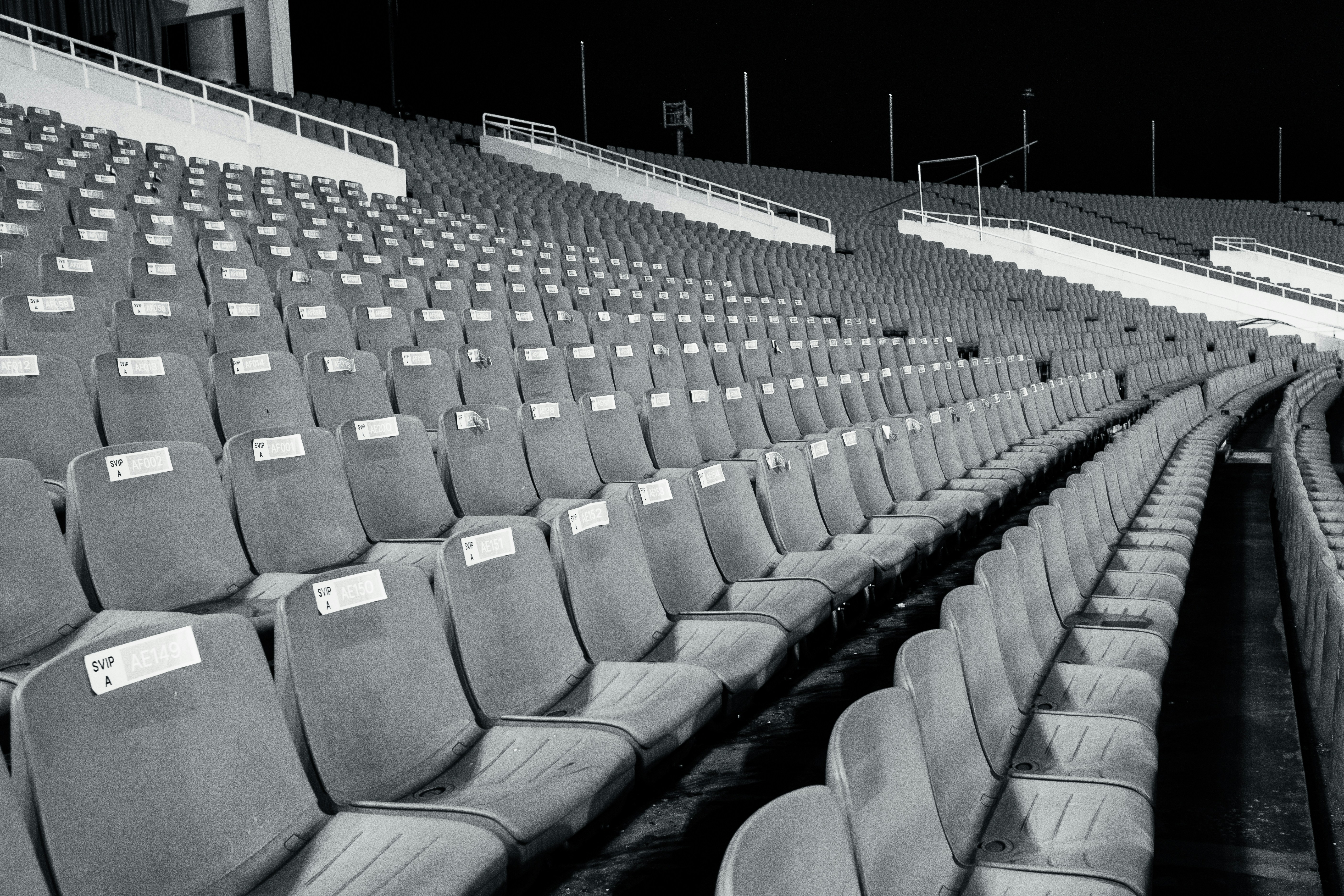Rows of empty stadium seats stretch into the distance under dim lighting.