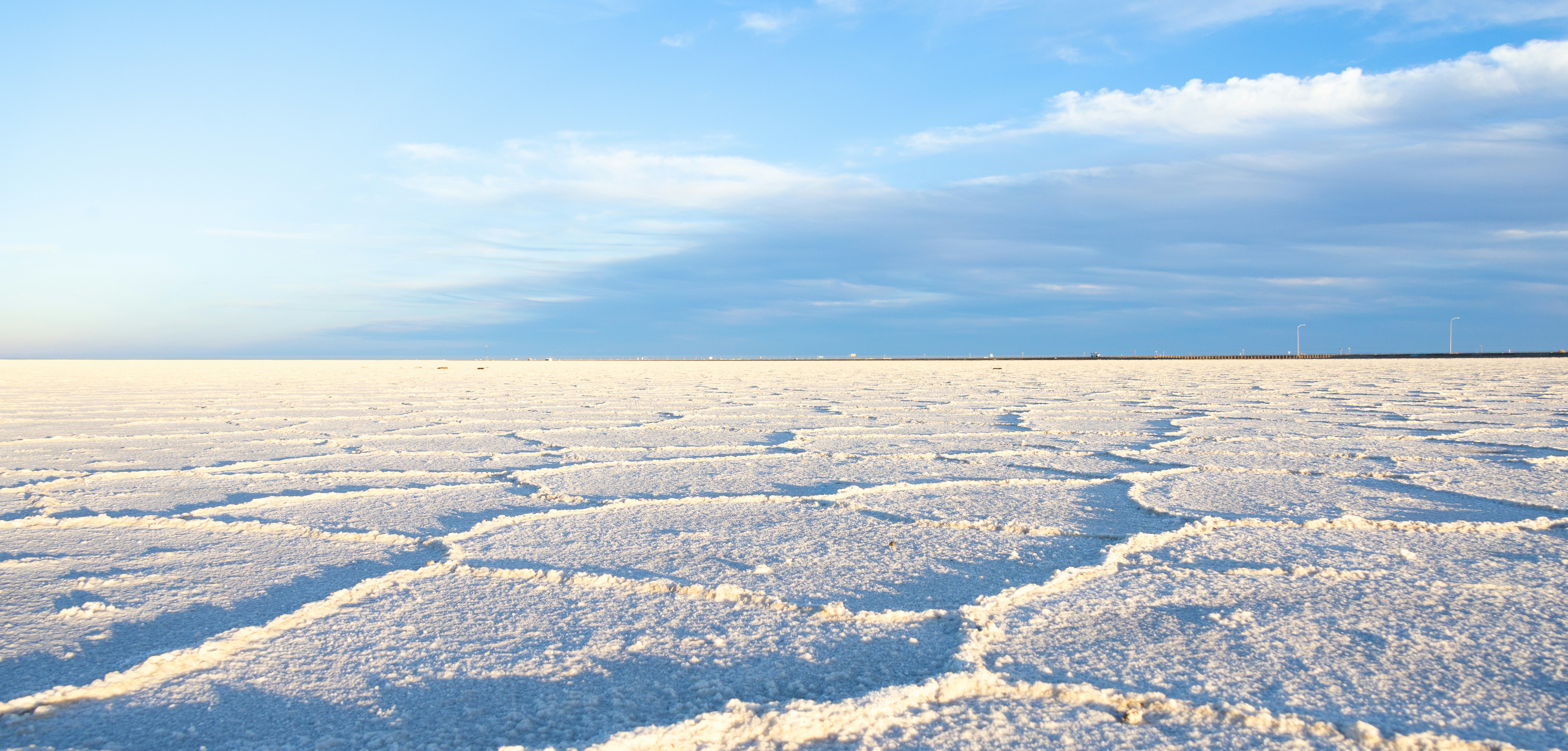 Hexagonal salt formations under a clear sky at the Bonneville Salt Flats.
