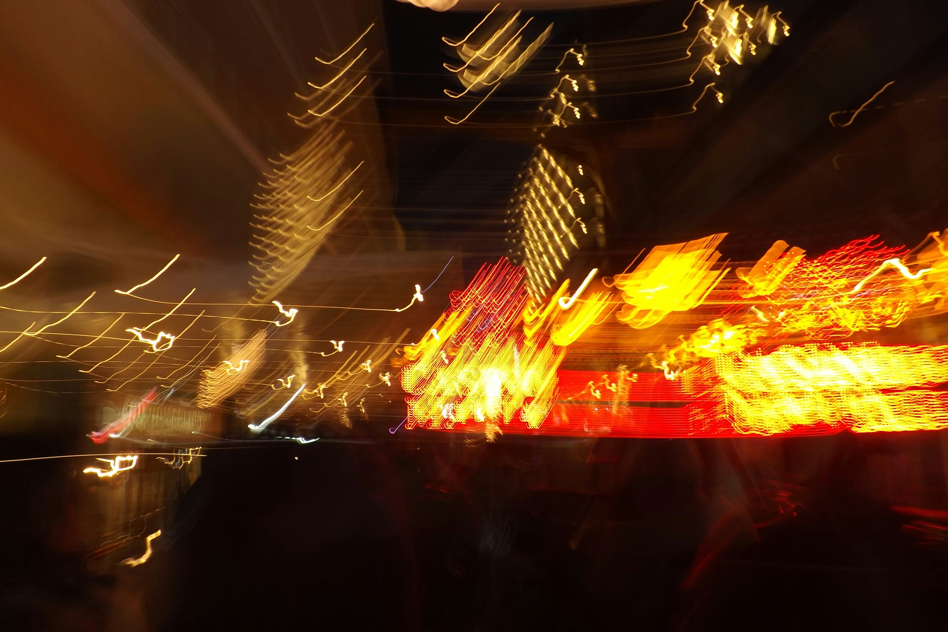 Streaks of colorful lights blur across a night cityscape, creating an abstract display of movement and energy.