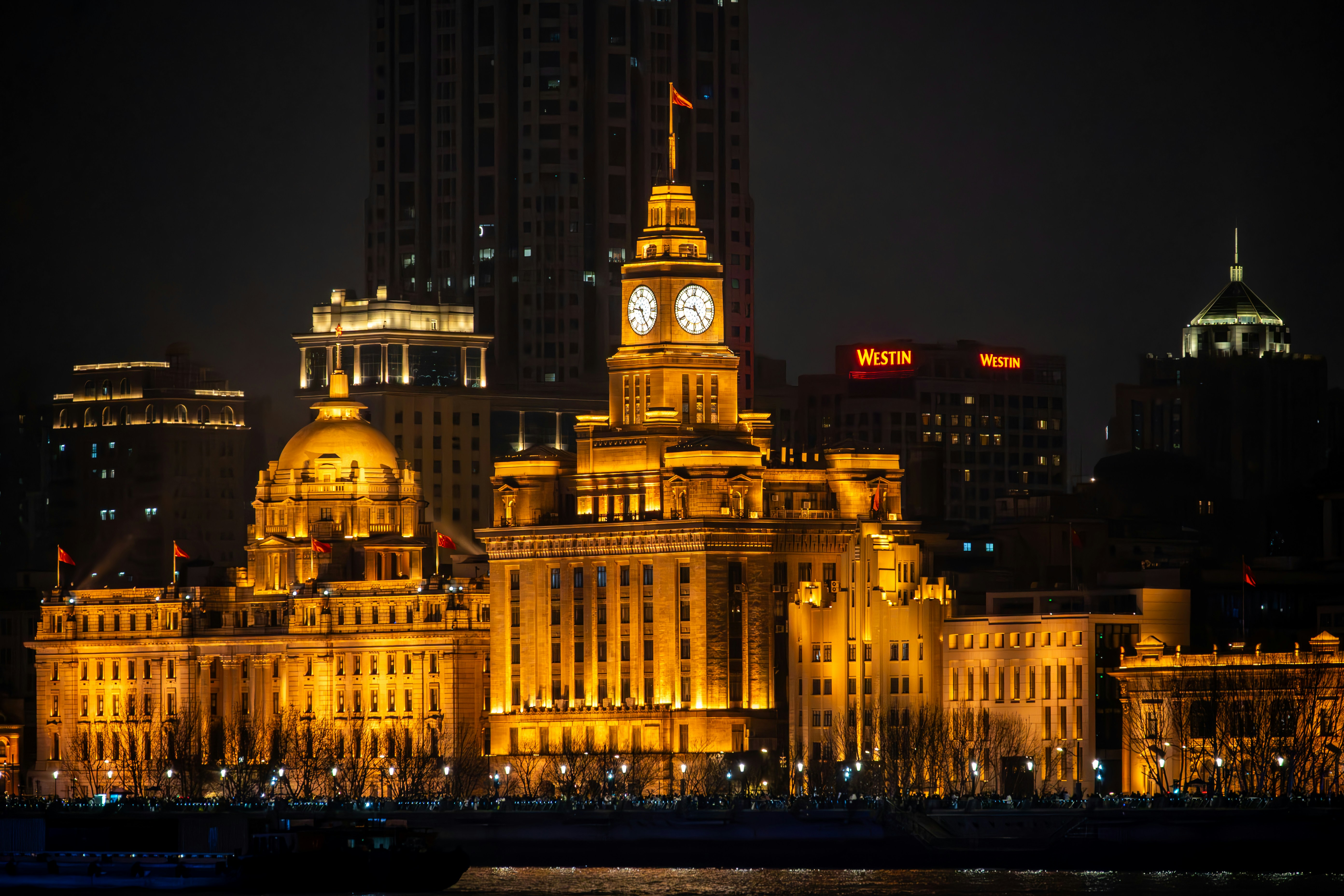 Illuminated historic buildings along a city waterfront at night.
