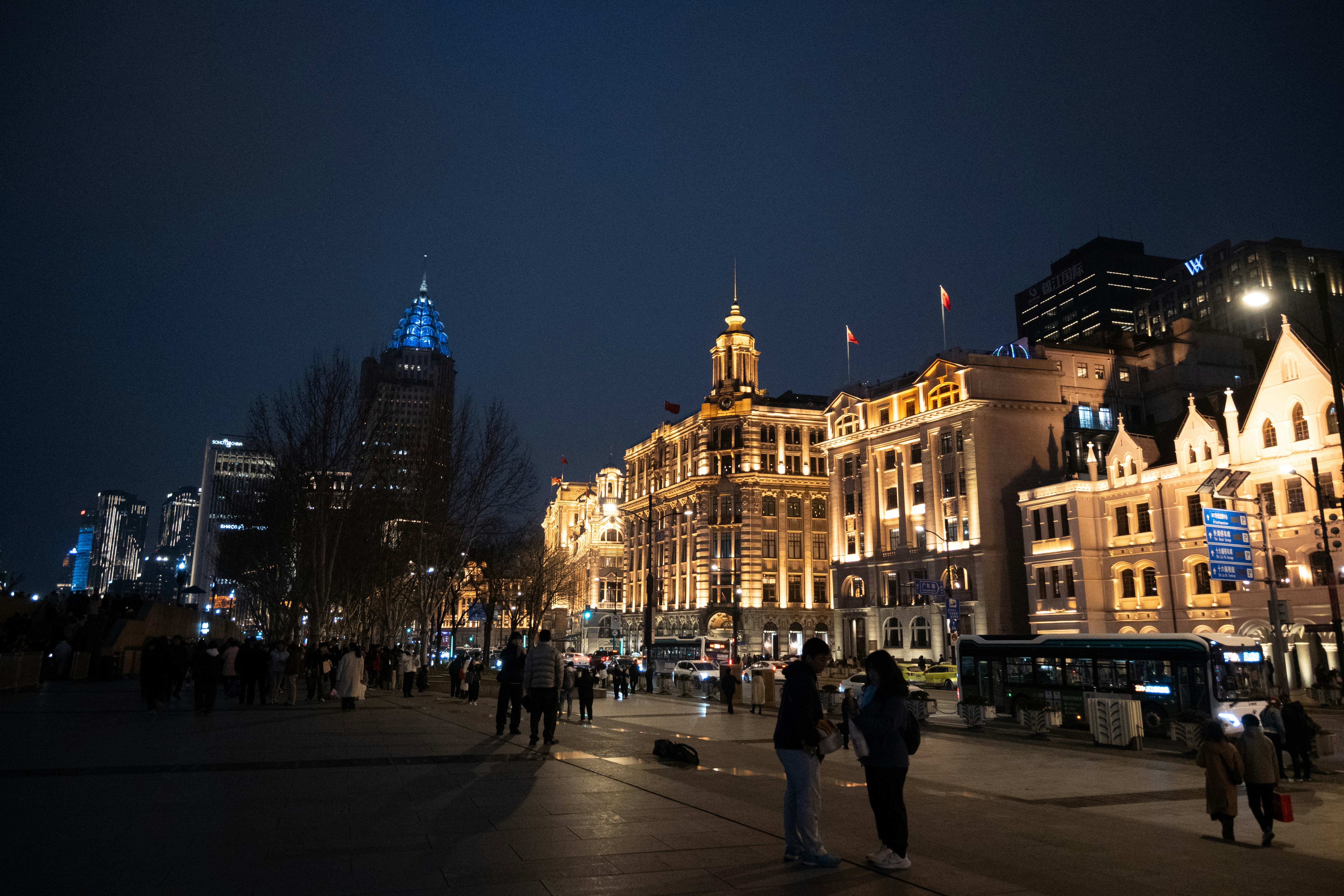 City skyline glowing with historic architecture and modern skyscrapers under a deep blue sky.