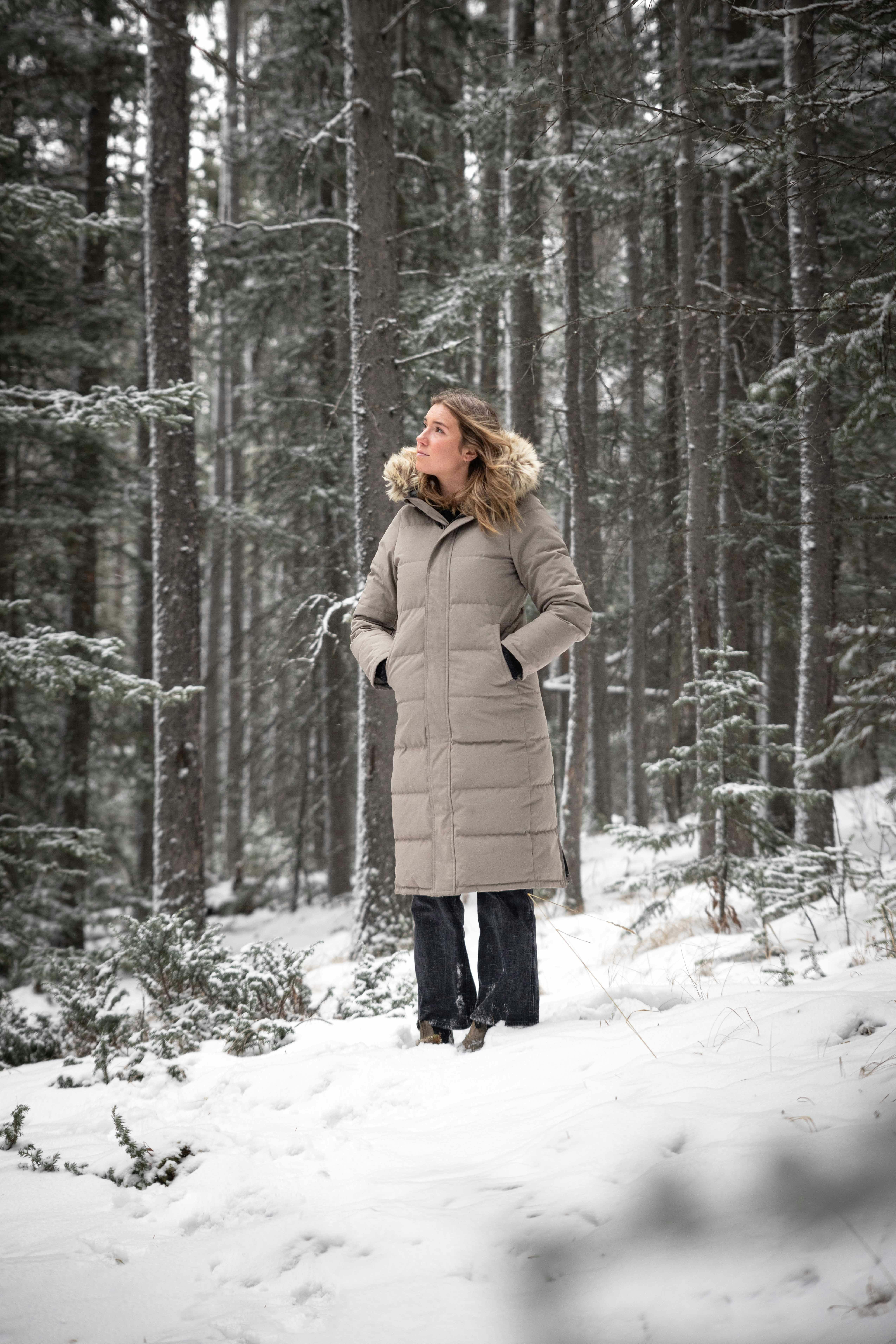 Young woman in a snowy forest glancing away.