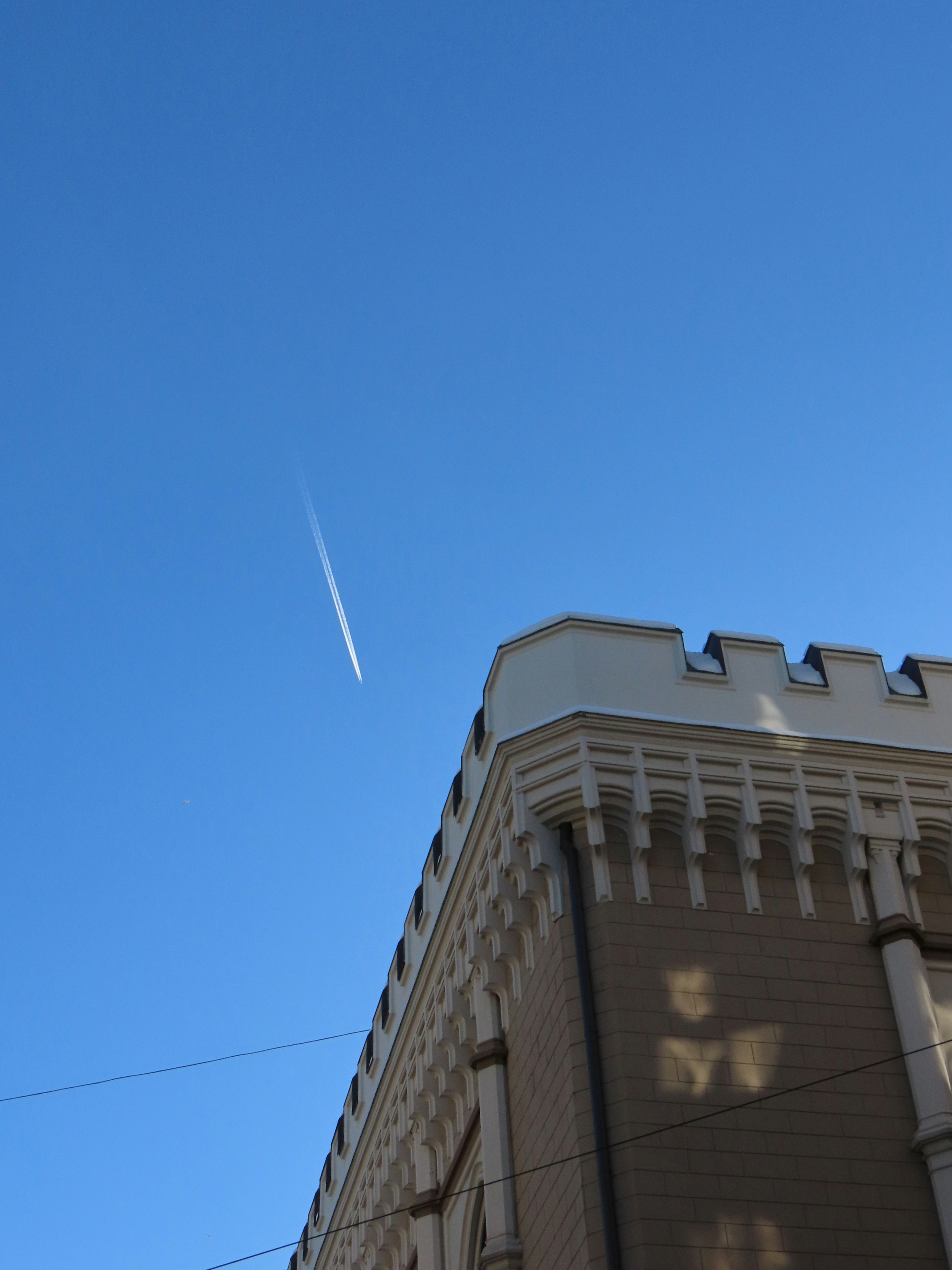 Contrail Slice Over a Castle-Style Corner on a Clear Day
