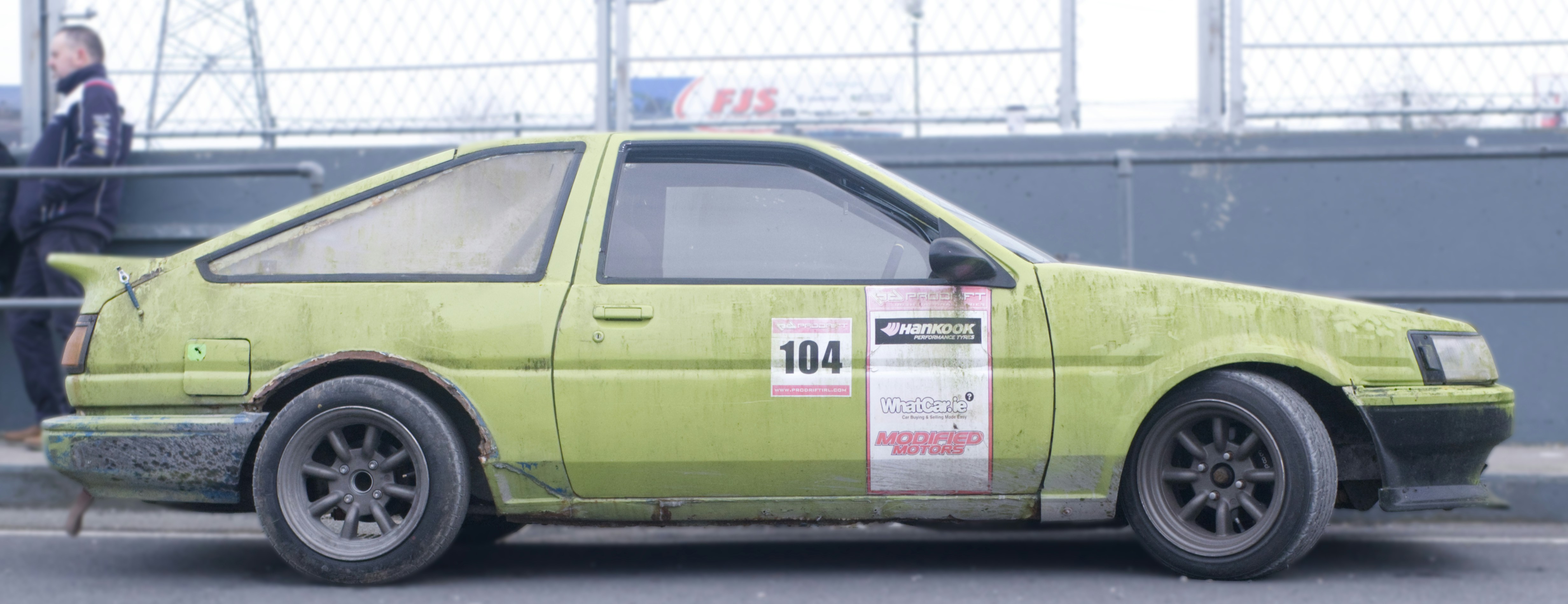 Neon Lime Rally Car No. 104 Paused by the Track Fence