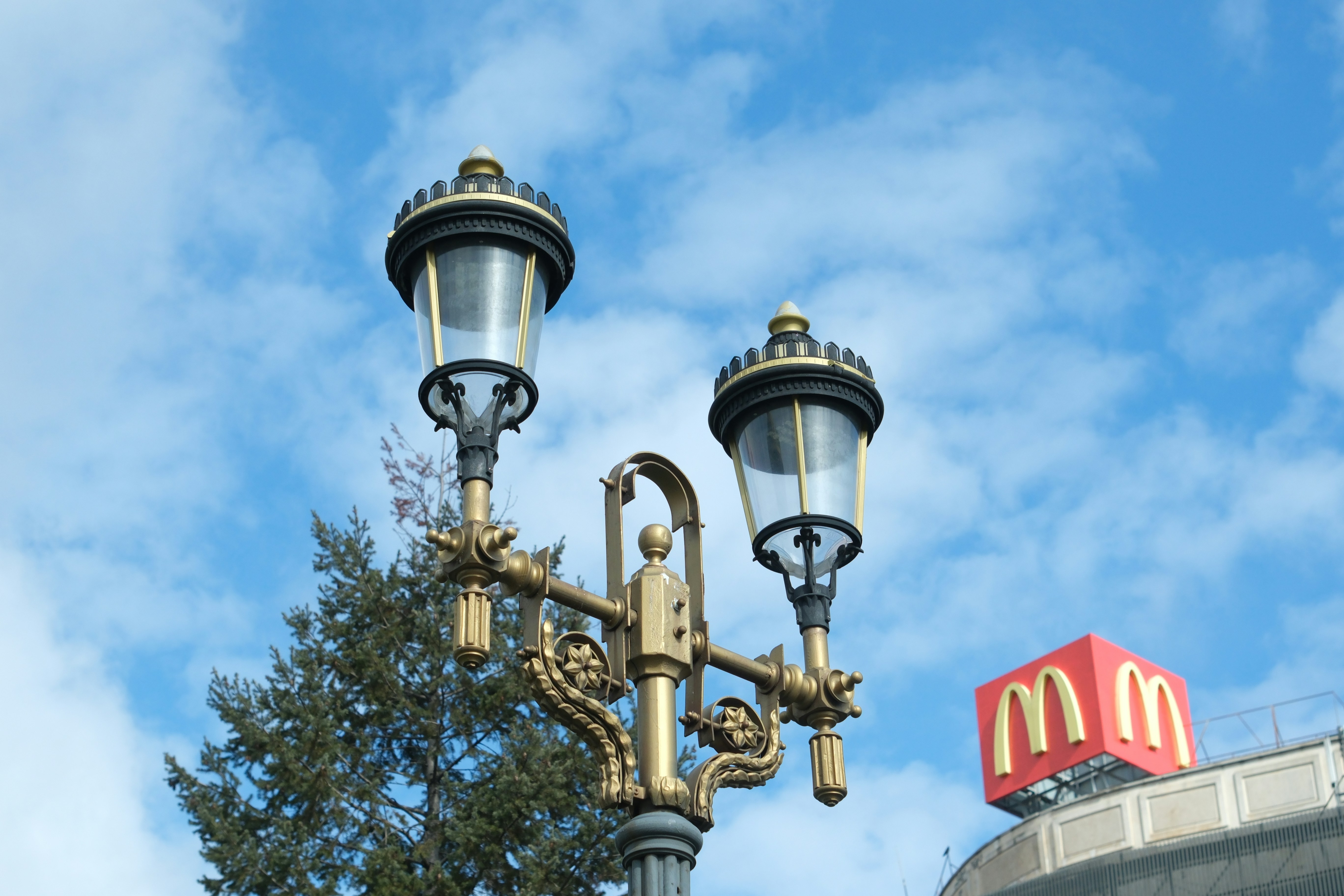 Bronze Lanterns Framing a Red M Against a Cerulean Sky