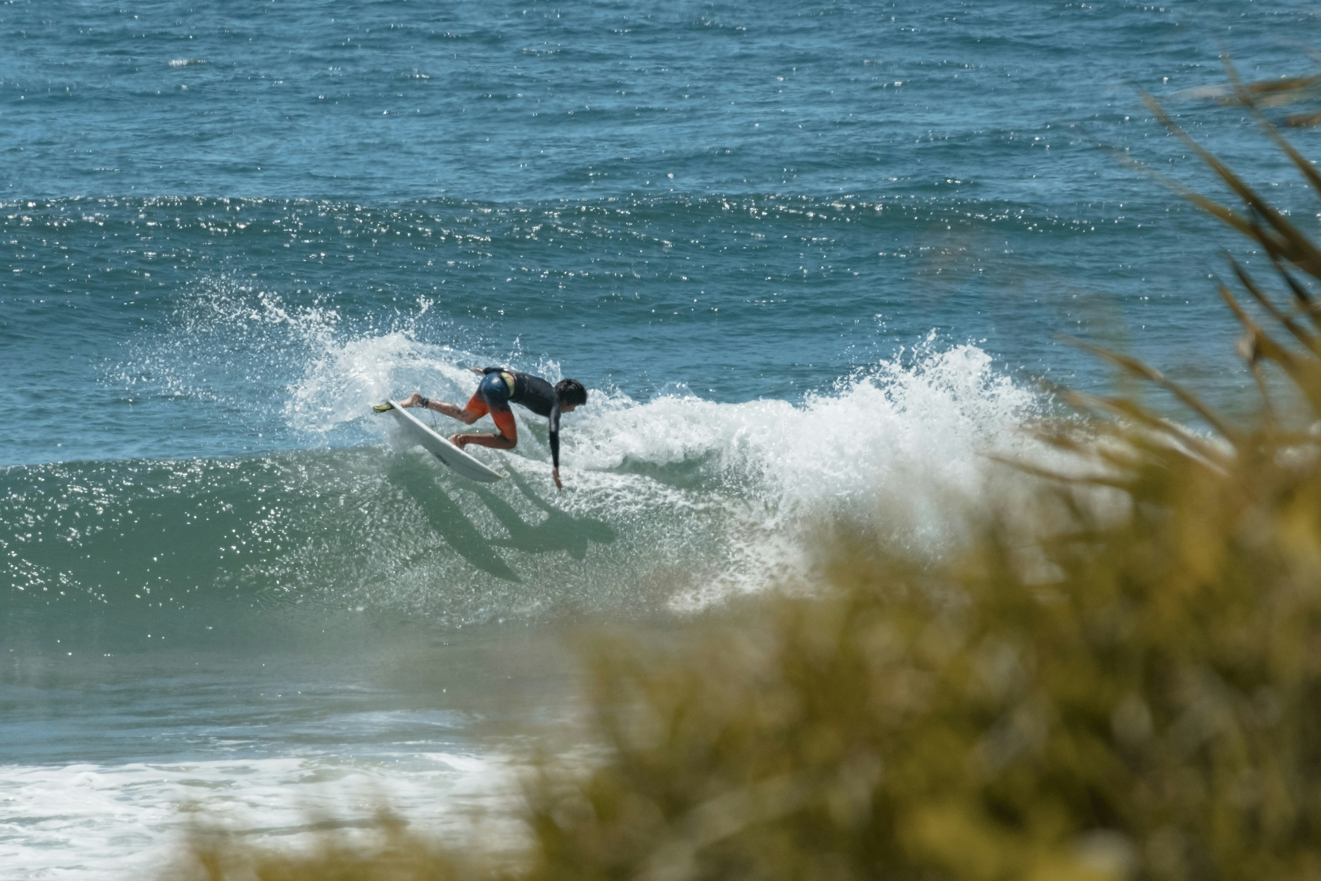 Surfer expertly carving through a wave against a backdrop of clear blue ocean.