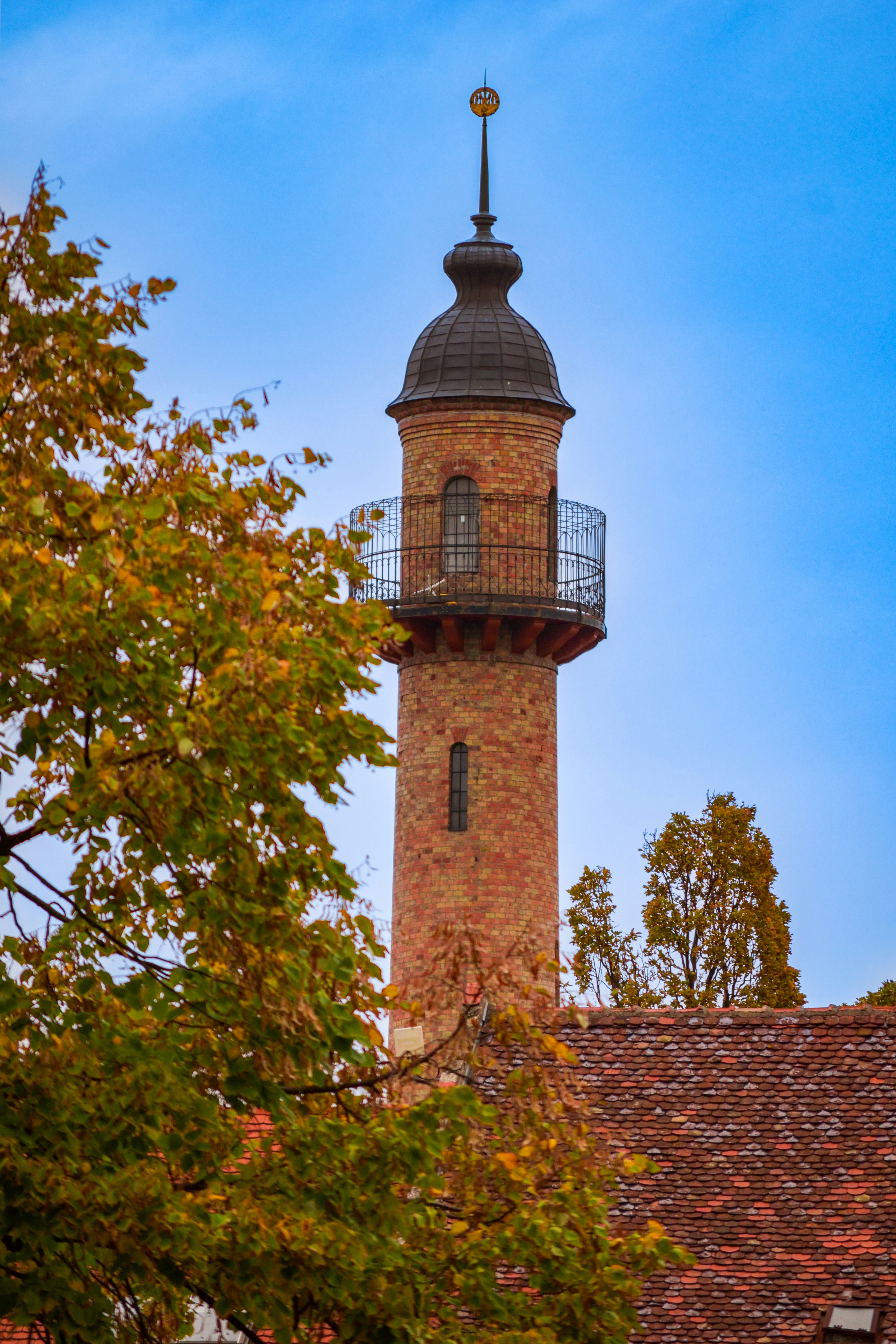 Brick Lantern Tower Under a Cerulean Sky, Framed by Autumn Foliage