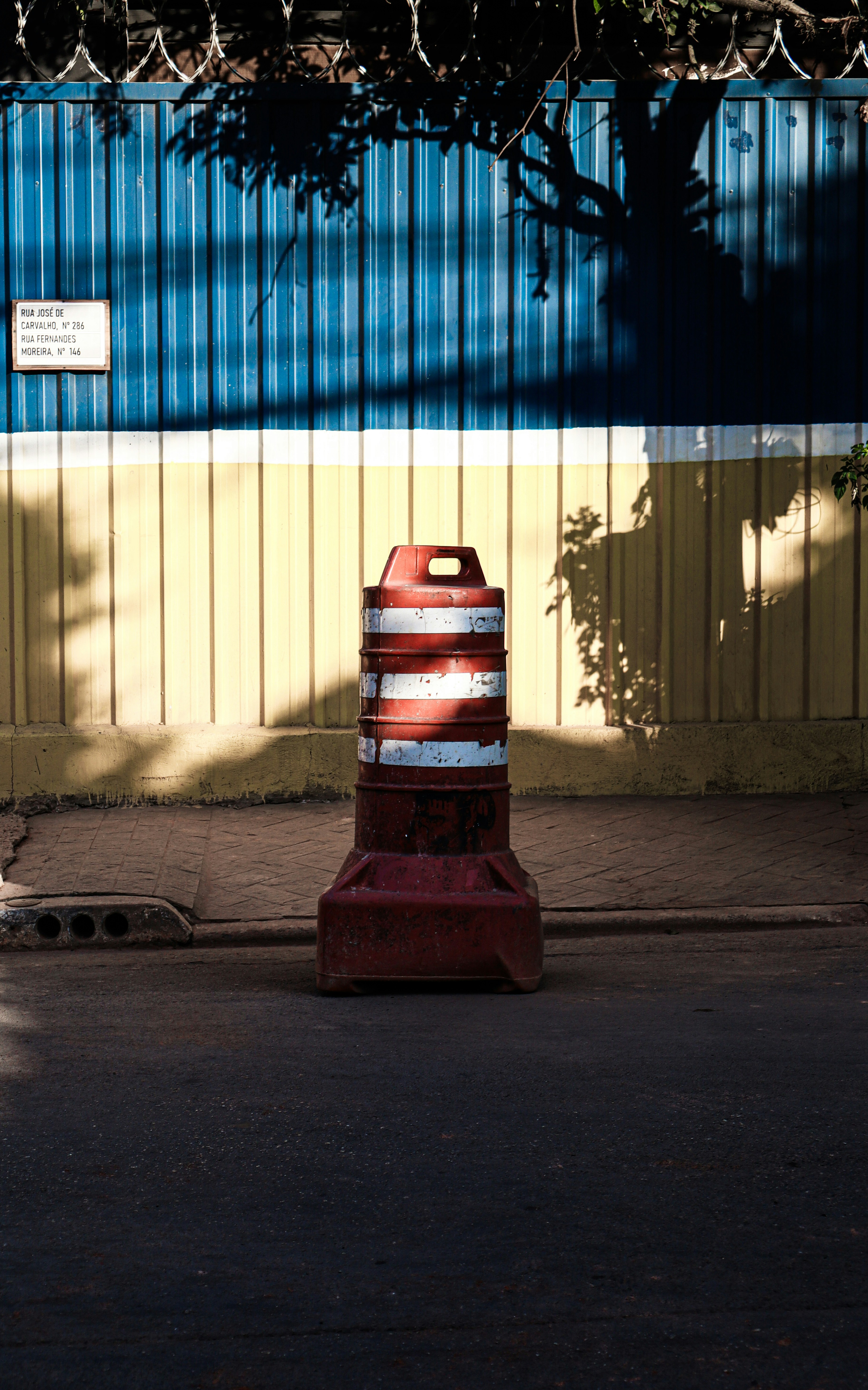 Red Barrier Between Blue Fence and Yellow Wall: A Street Portrait