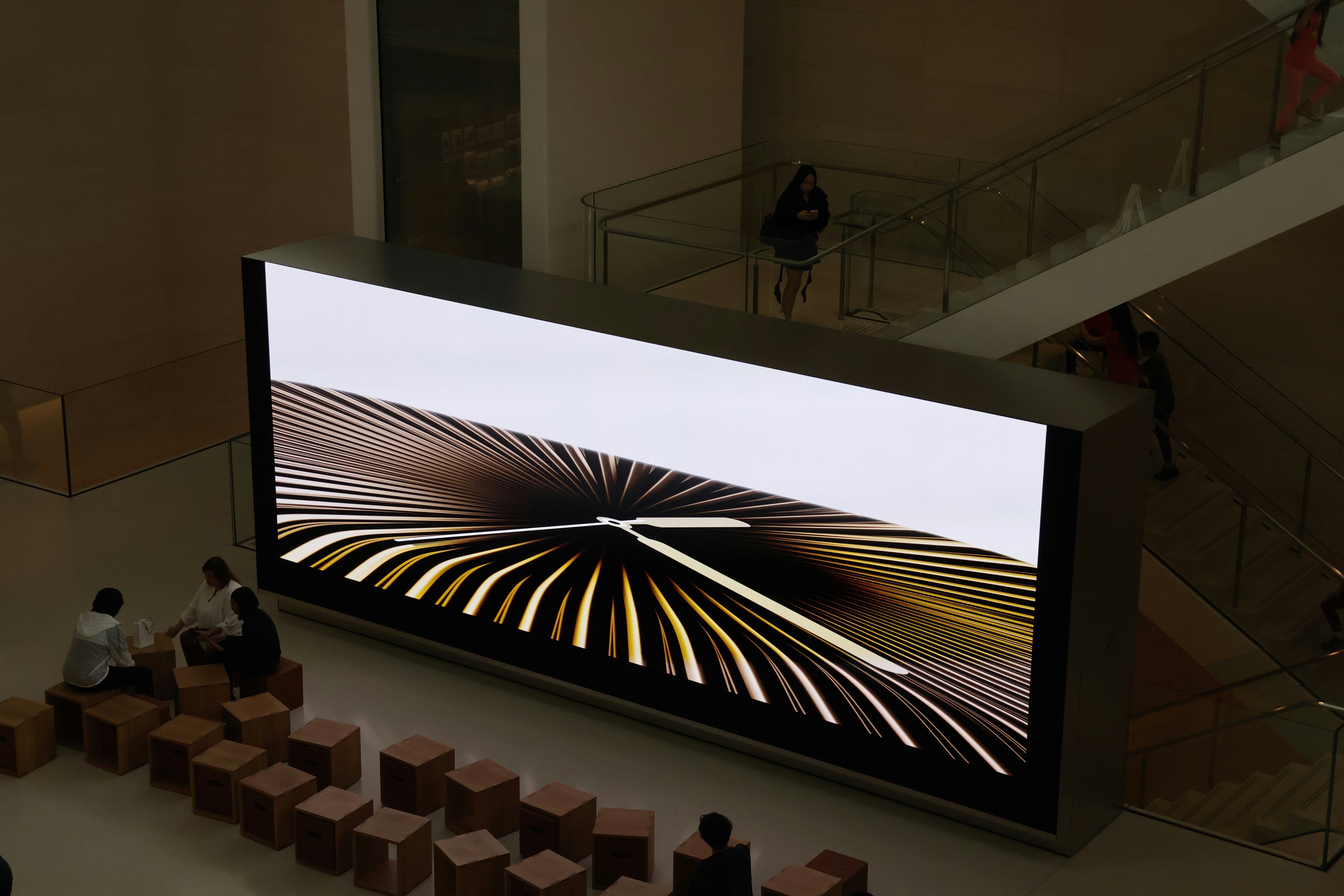 Large digital display with abstract art in a modern indoor setting.