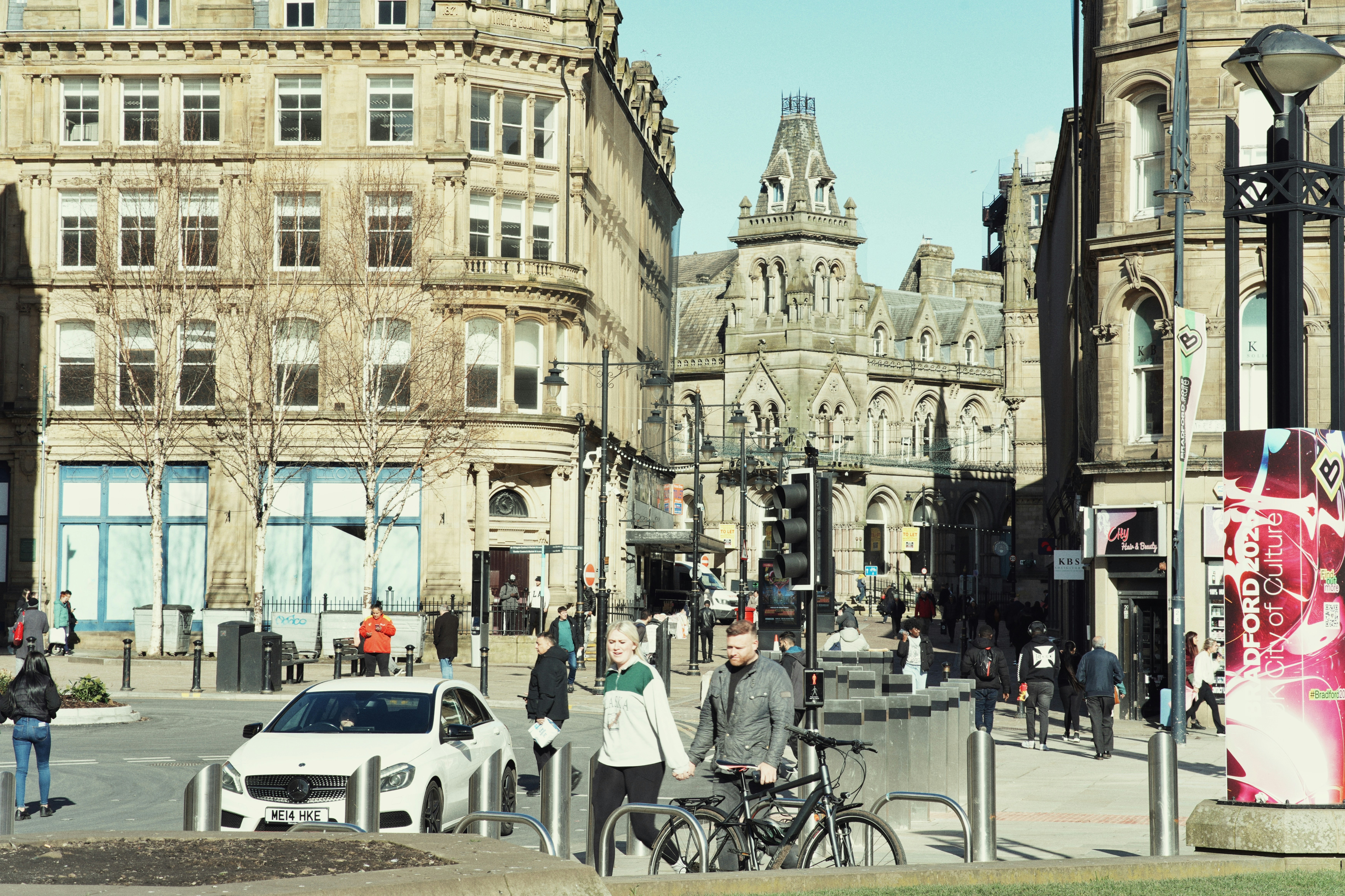Historic buildings and modern life converge on a bustling city street.