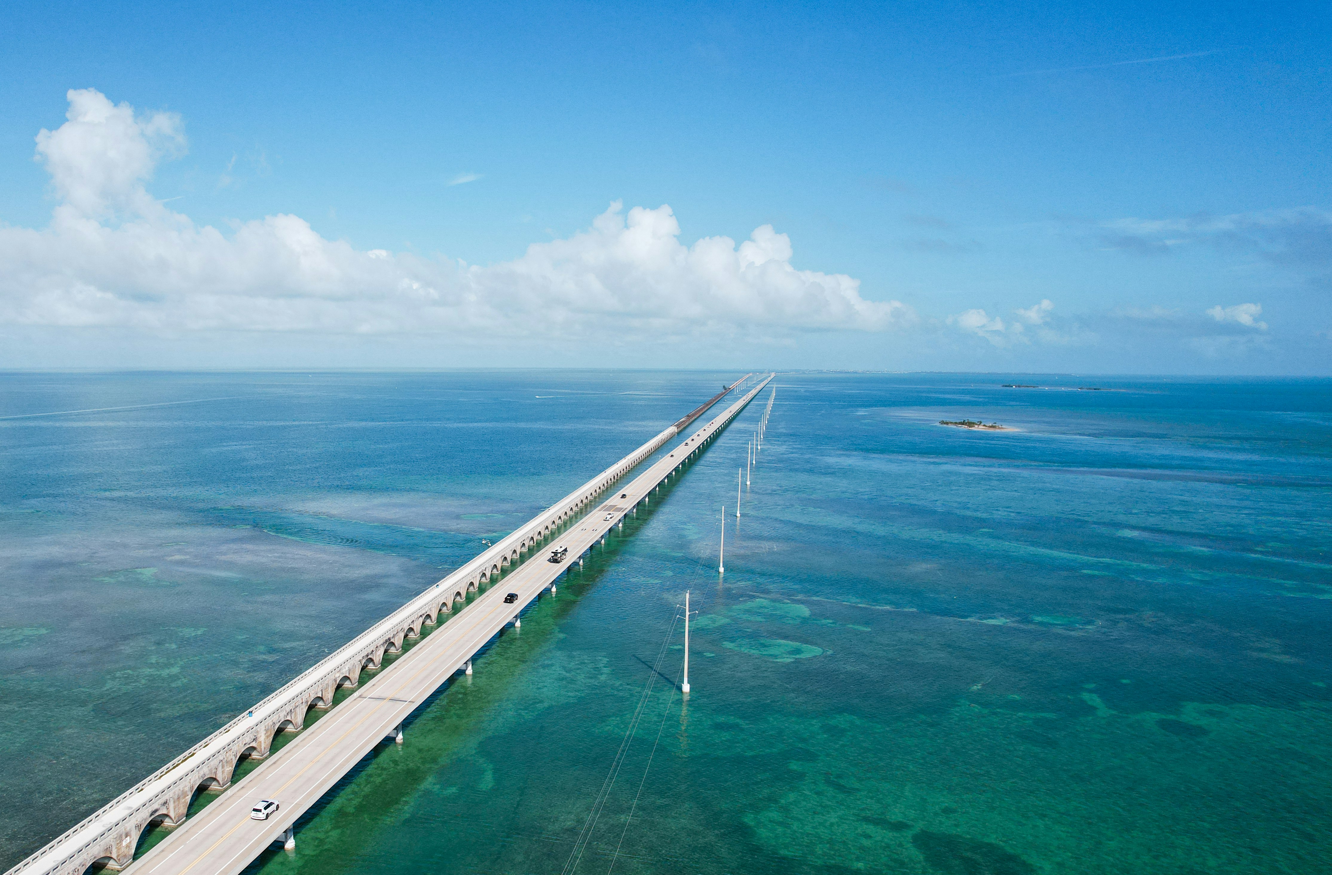 Aerial view of the expansive Seven Mile Bridge stretching across turquoise waters under a clear blue sky.