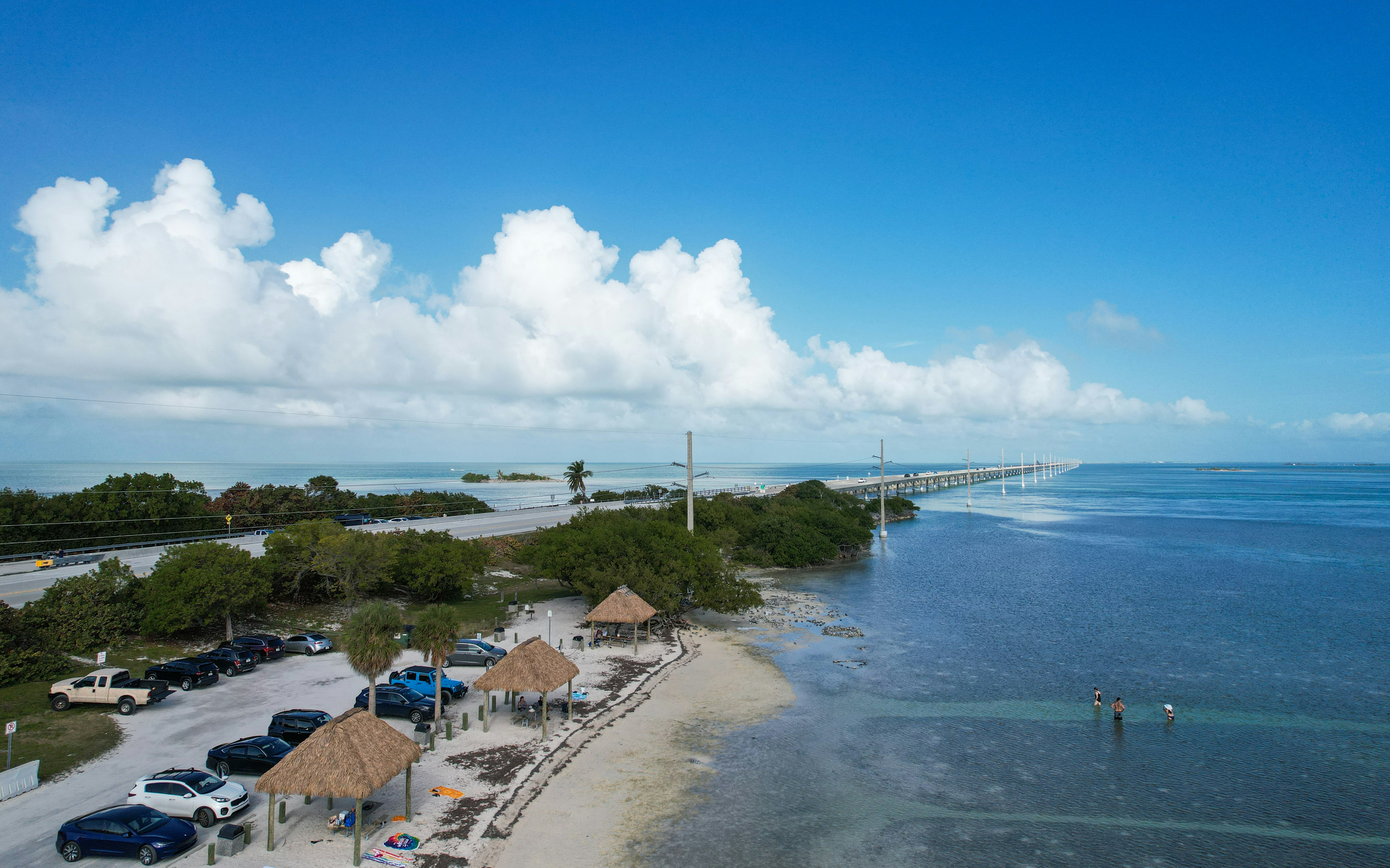 Aerial view of the Seven Mile Bridge stretching across the turquoise waters of the Florida Keys with scattered clouds in the sky.