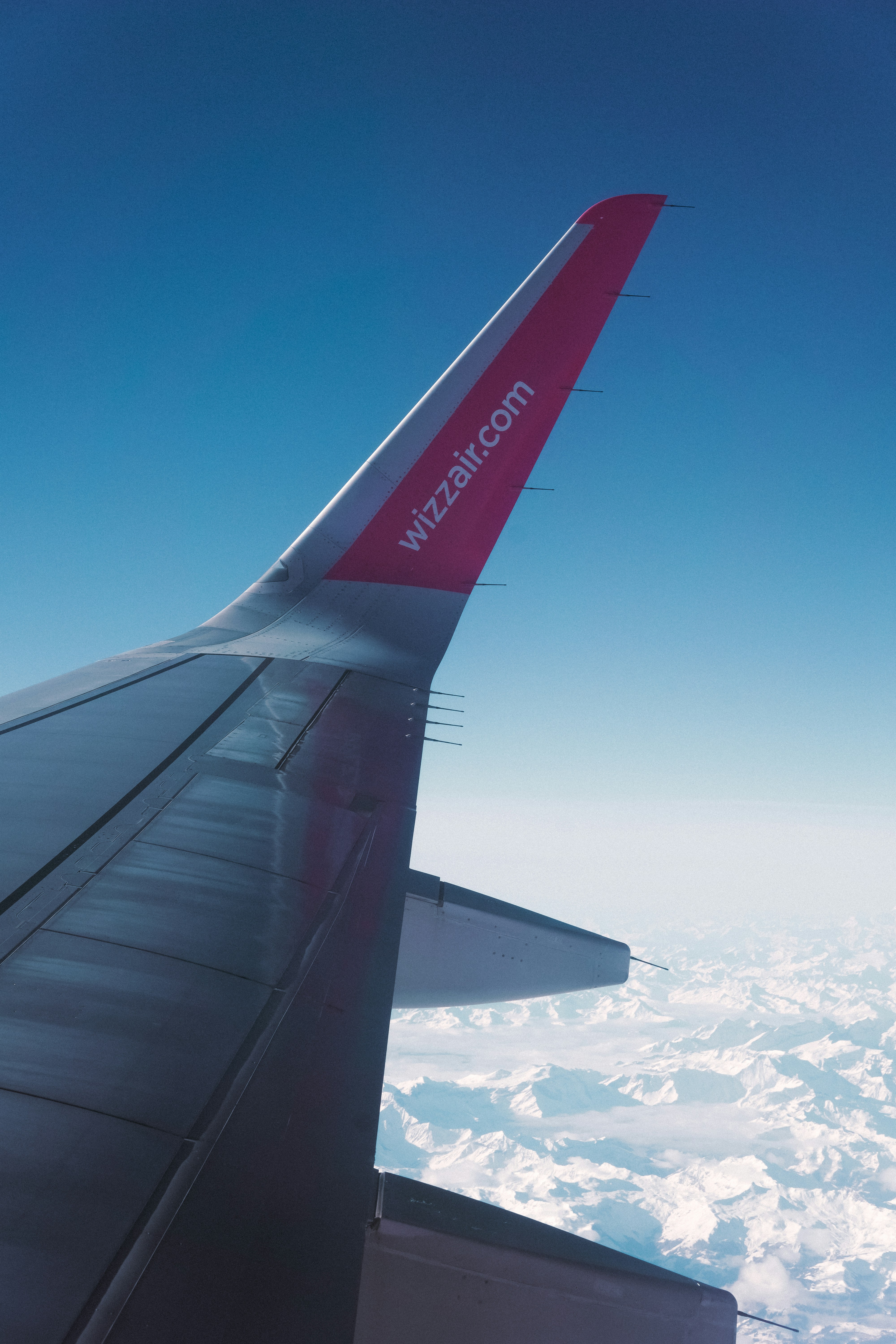 A wizz air wing is flying high in the sky. photo – Free Travel Image on ...