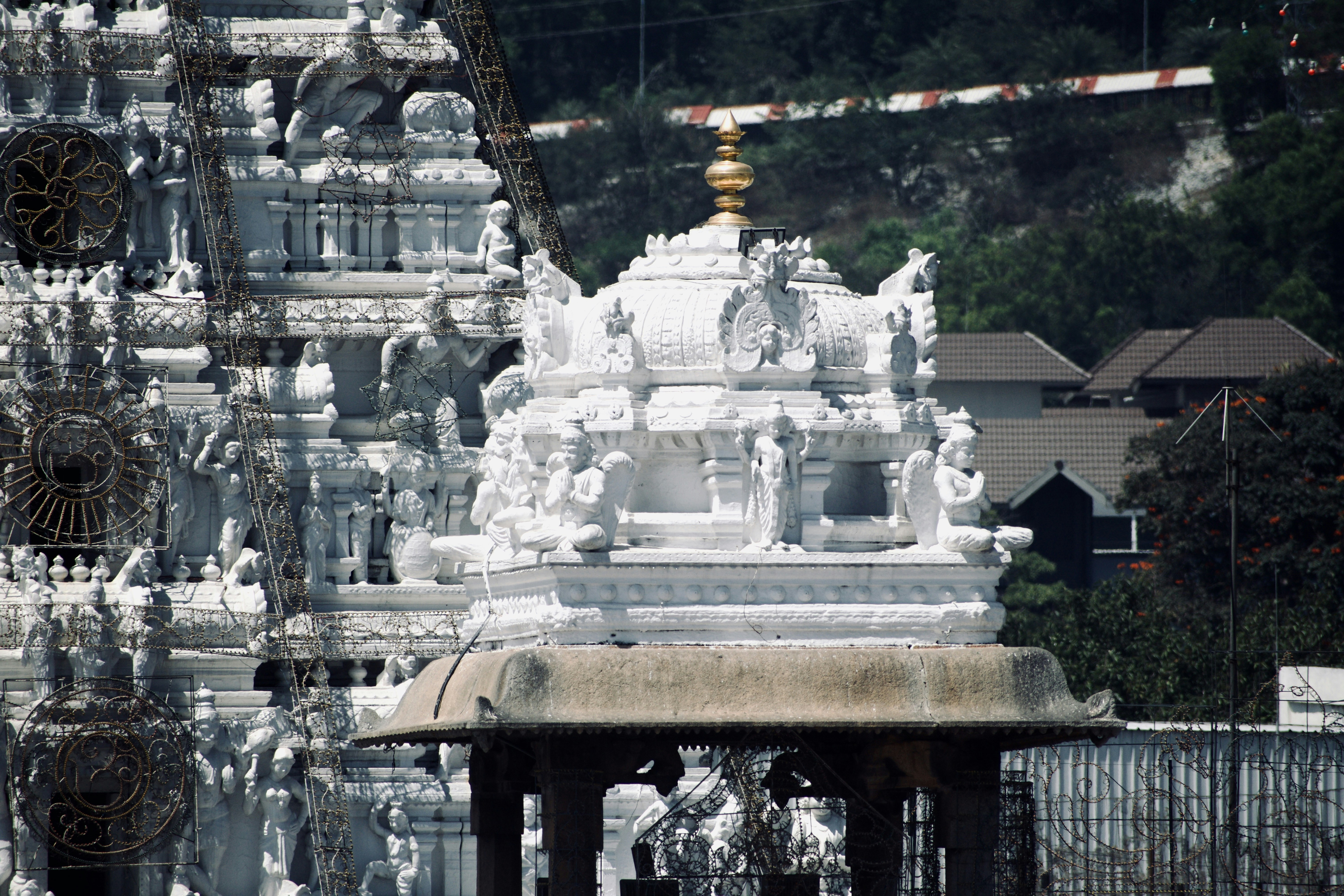 Intricately carved white temple structures adorned with statues under a clear sky.