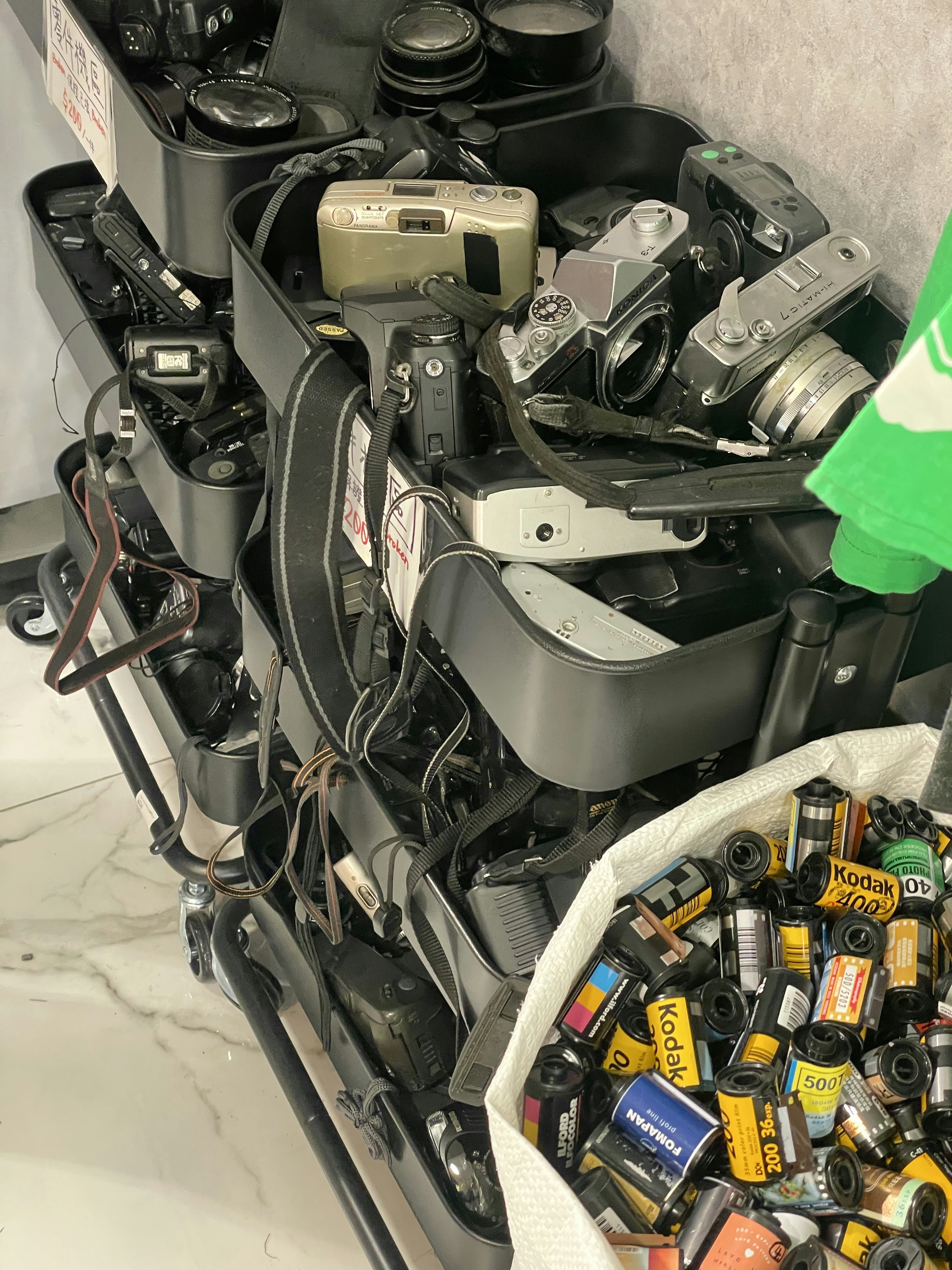 Stack of vintage cameras and junked gear in a cluttered shelf