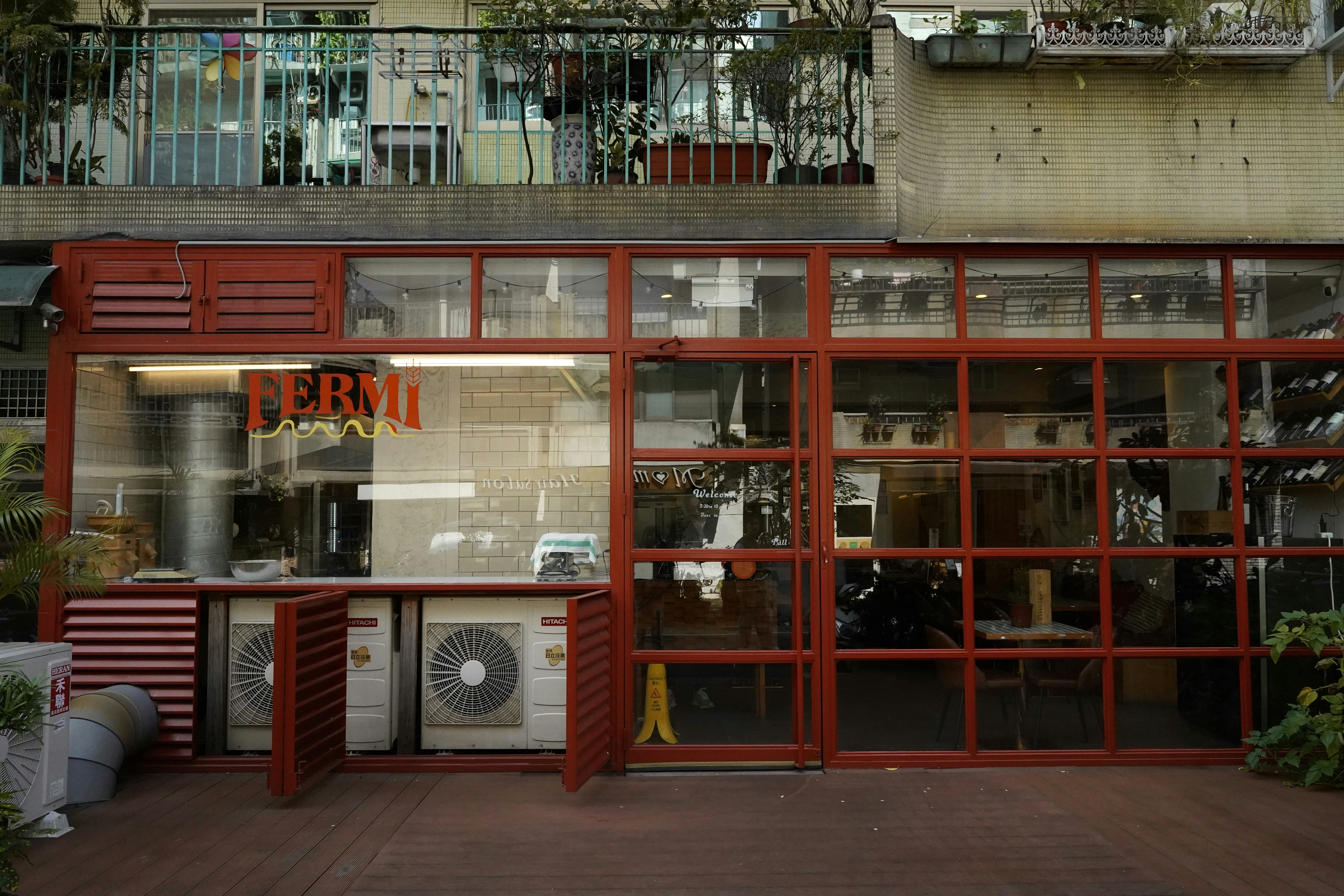 Red-framed storefront with large glass windows and urban reflections.