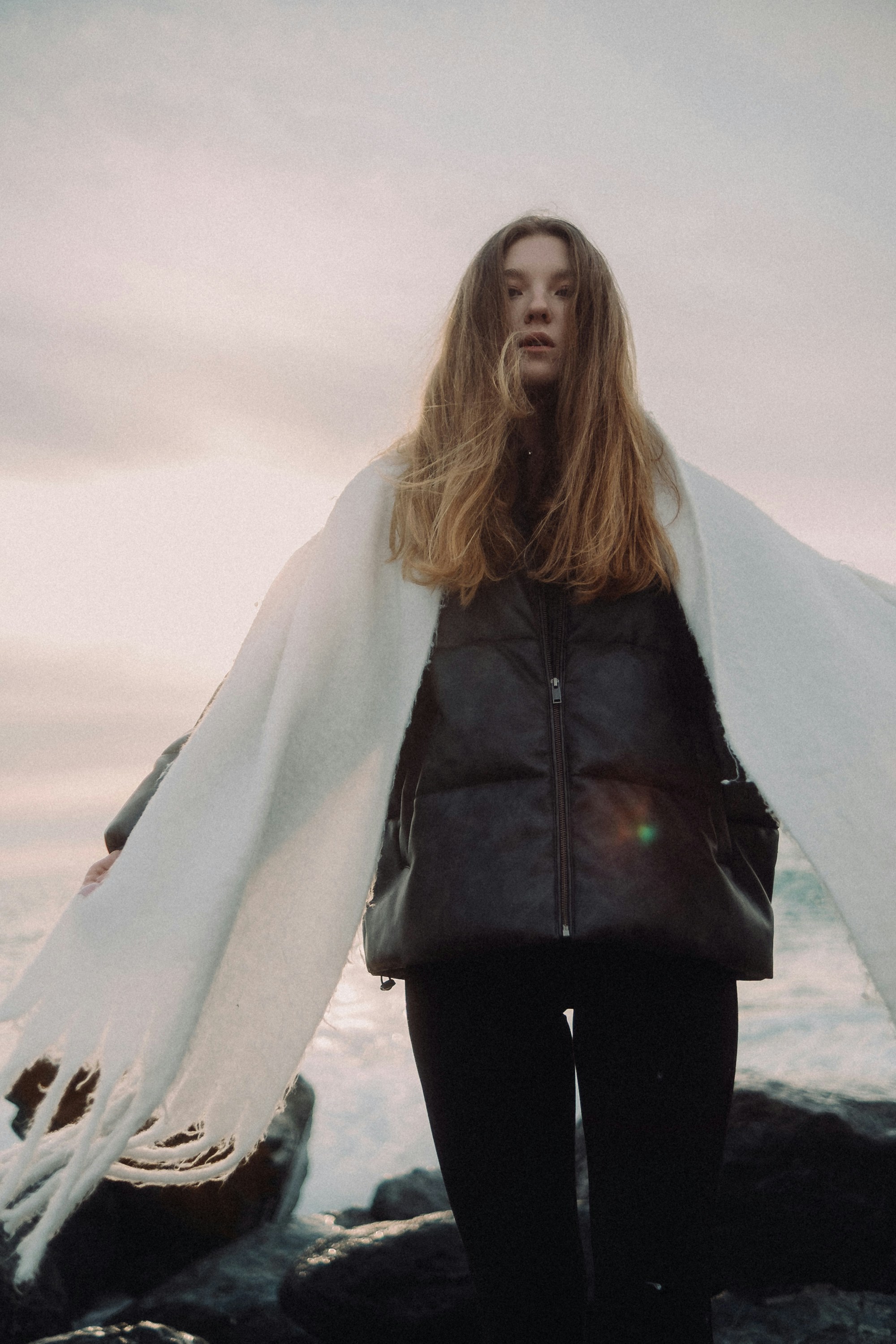 Coastal Spotlight: A Woman Draped in White on a Windy Cliffside