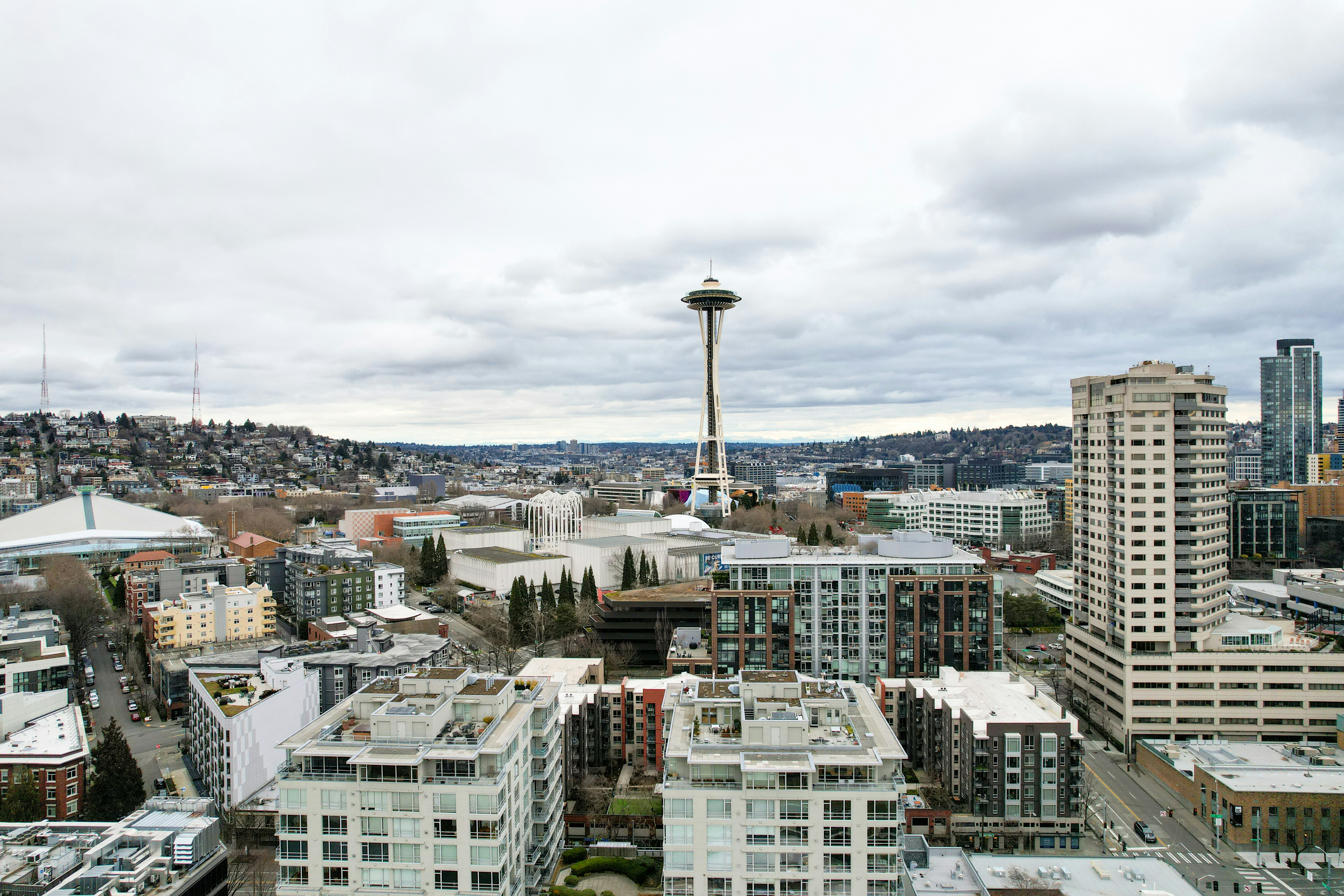 Seattle's Space Needle rises above the urban landscape under a cloudy sky.