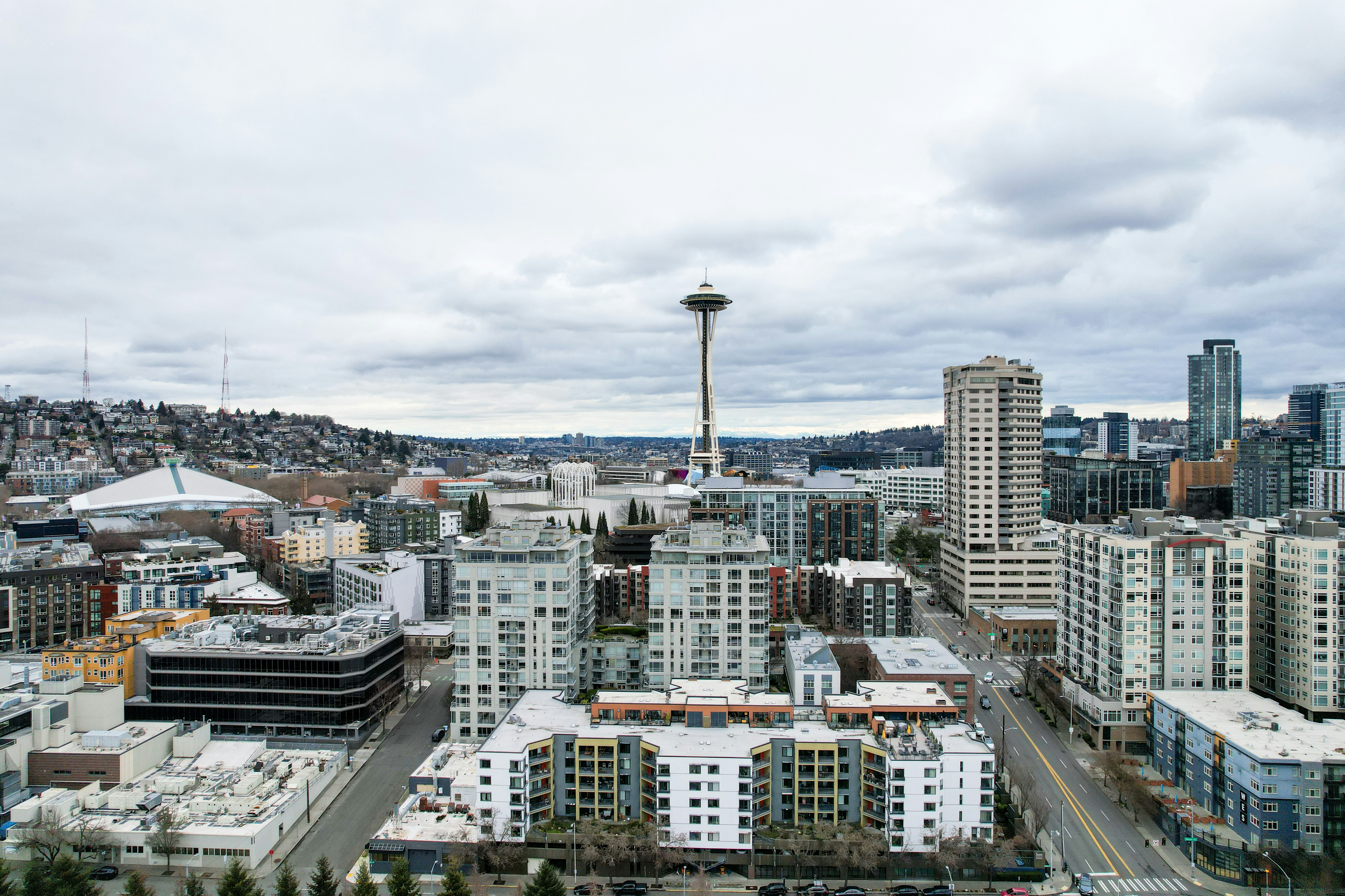 Seattle skyline with the Space Needle framed by modern architecture under a cloudy sky.