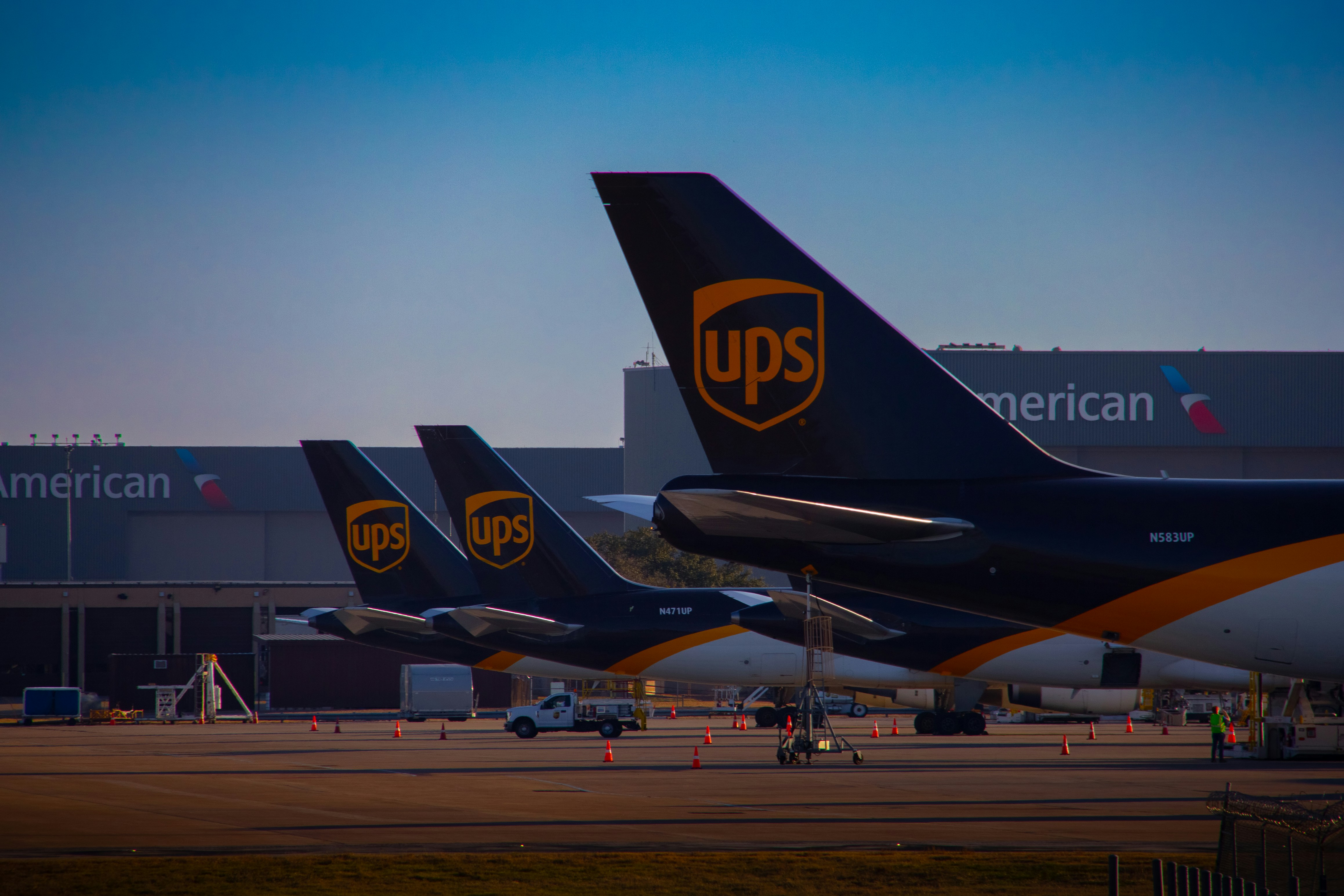UPS planes lined up at an airport with a clear blue sky.
