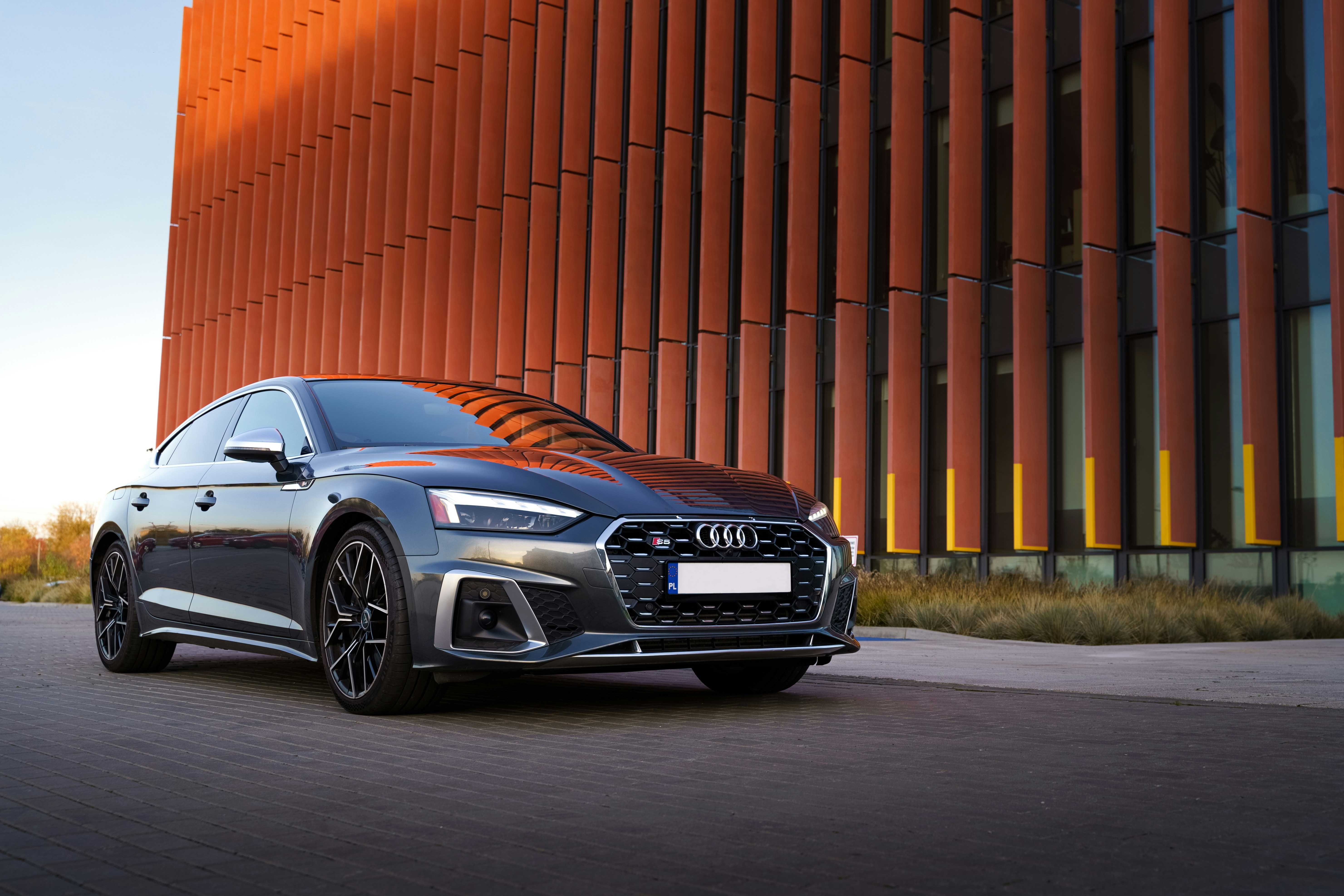 An audi sits in front of a tall building. photo – Free Car Image on ...