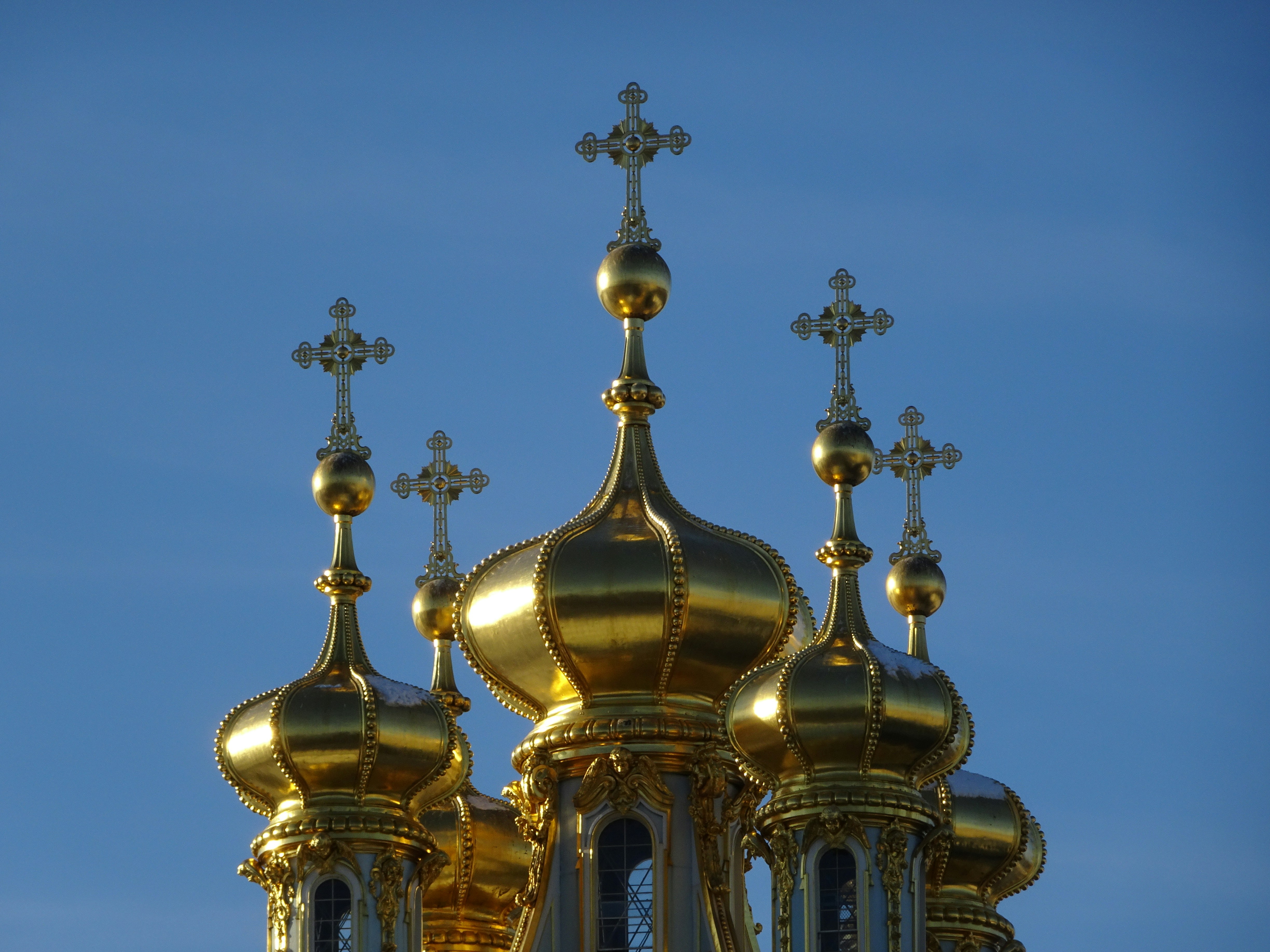 Ornate golden domes with crosses glisten under a clear blue sky.