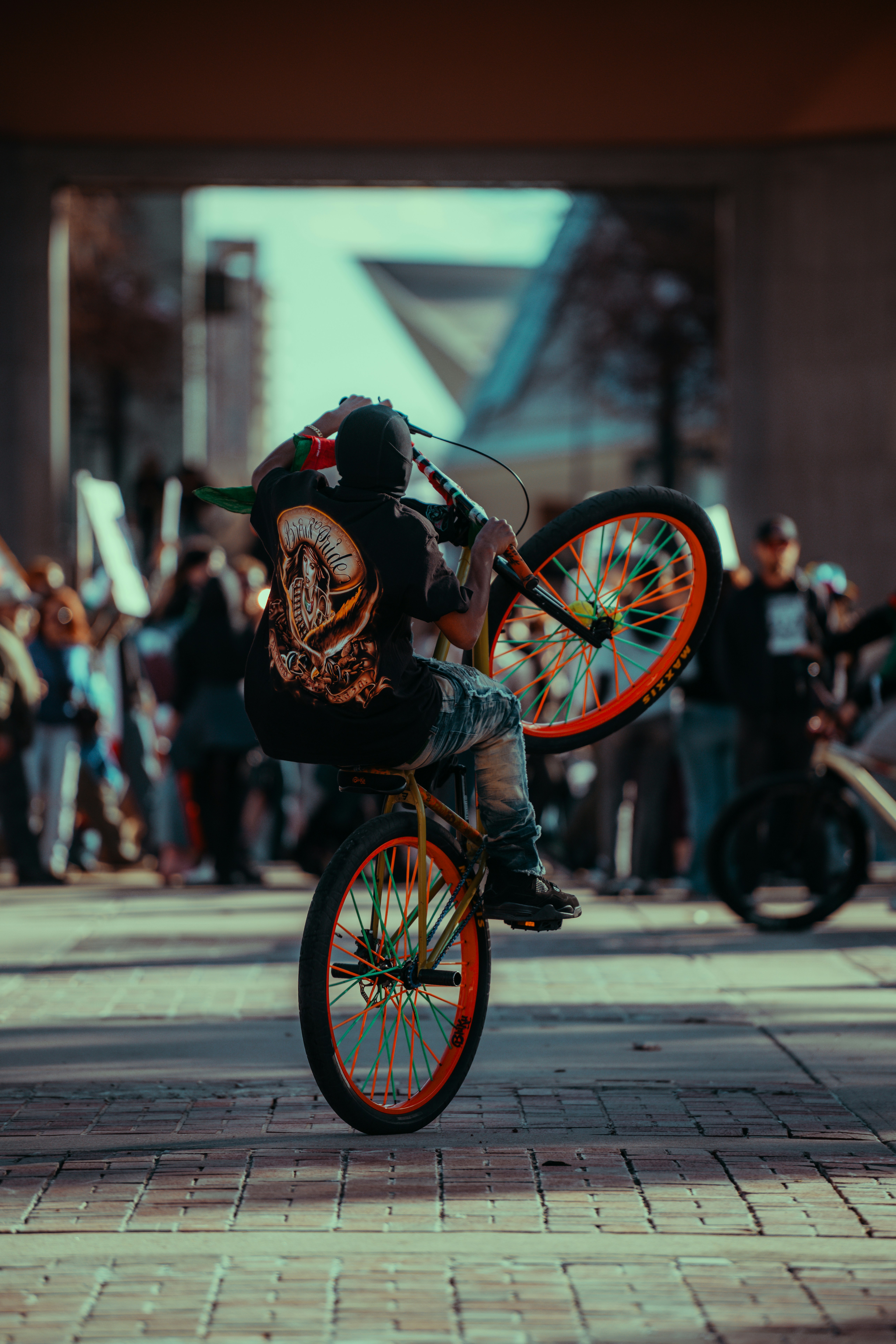 Urban Wheelie in the Plaza: Neon-Orange BMX Rims Slice Through a Curious Crowd
