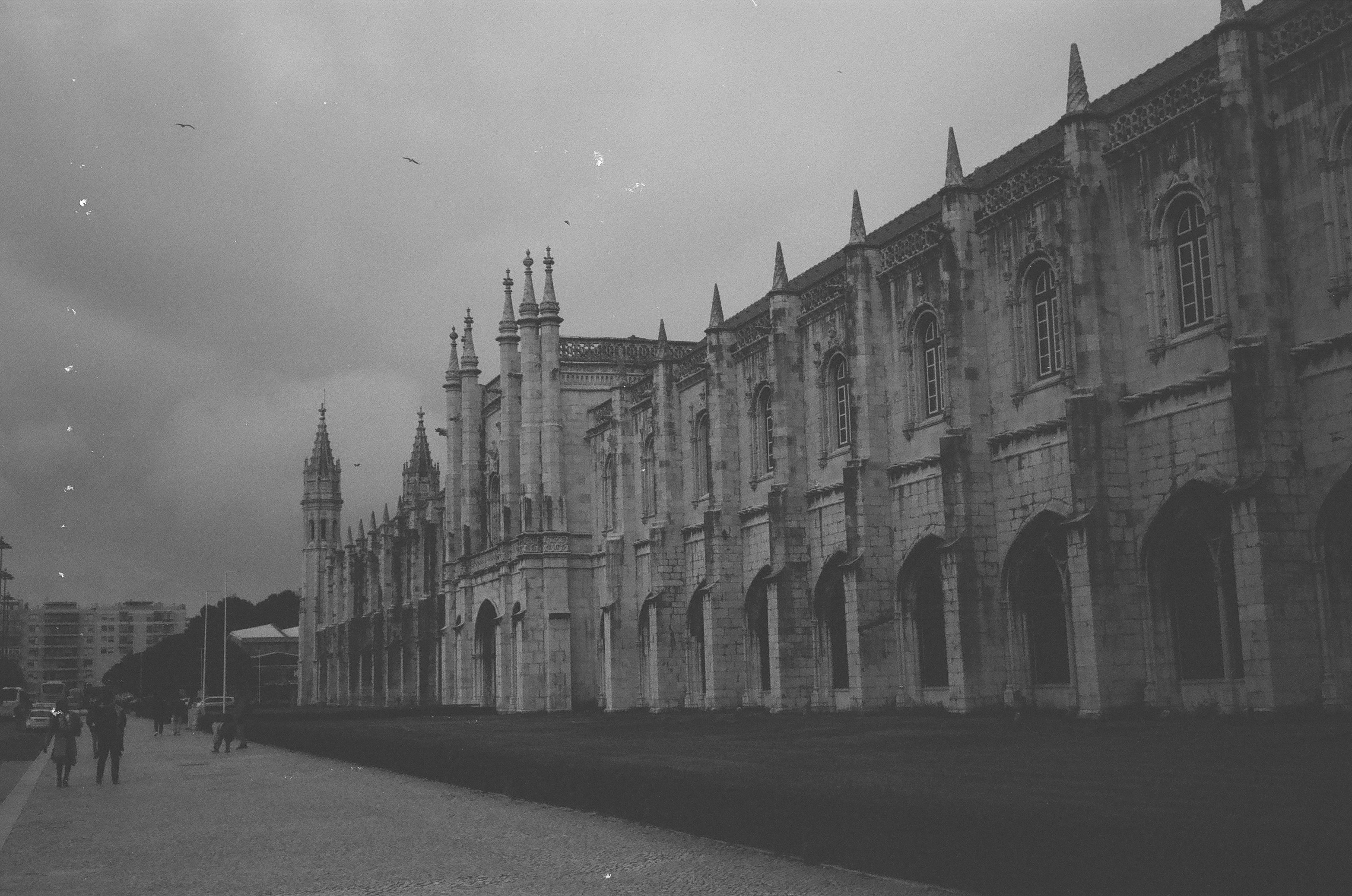 Historic stone building with ornate spires under a cloudy sky.