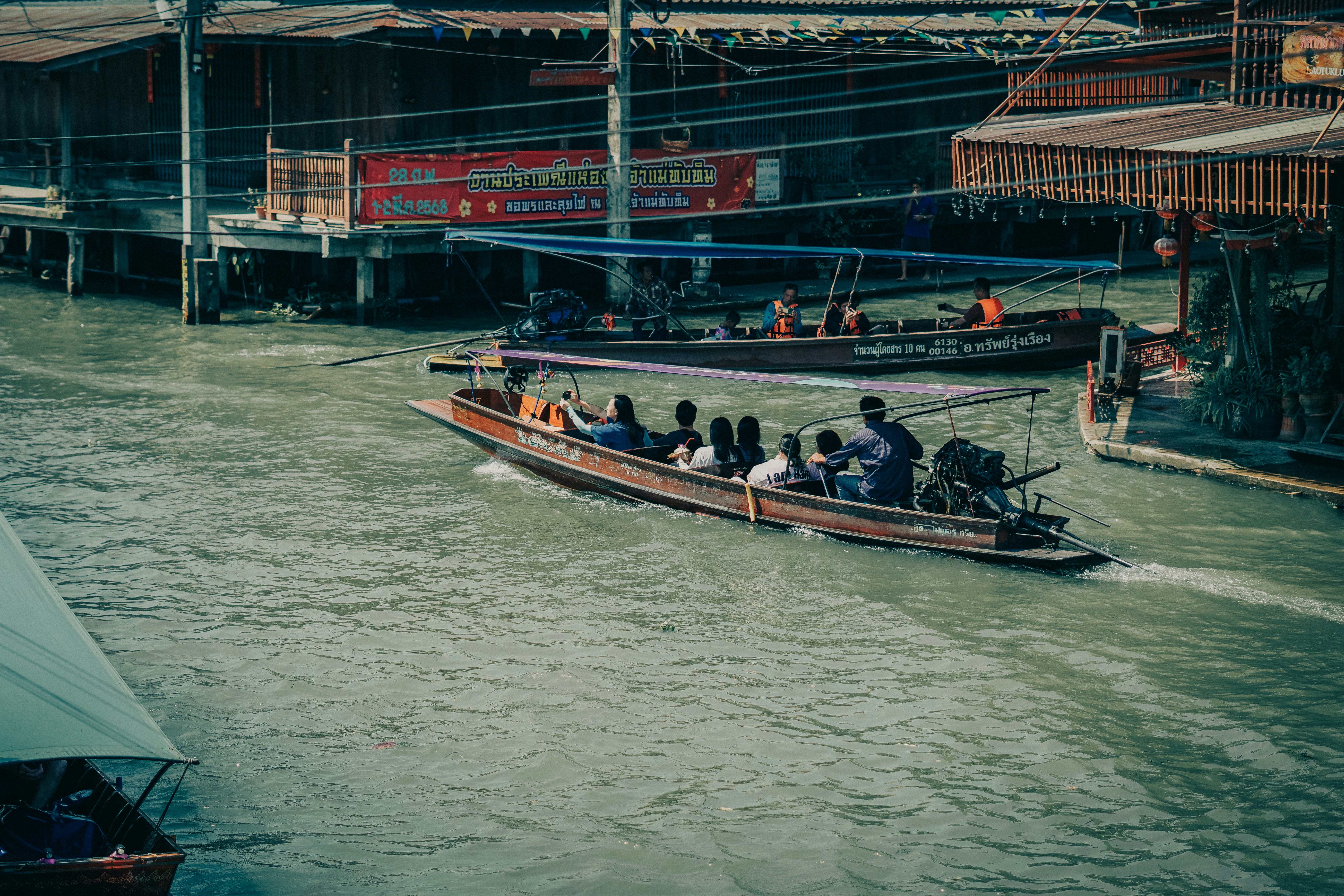 Boats navigate a waterway near buildings. photo – Free Human Image on ...