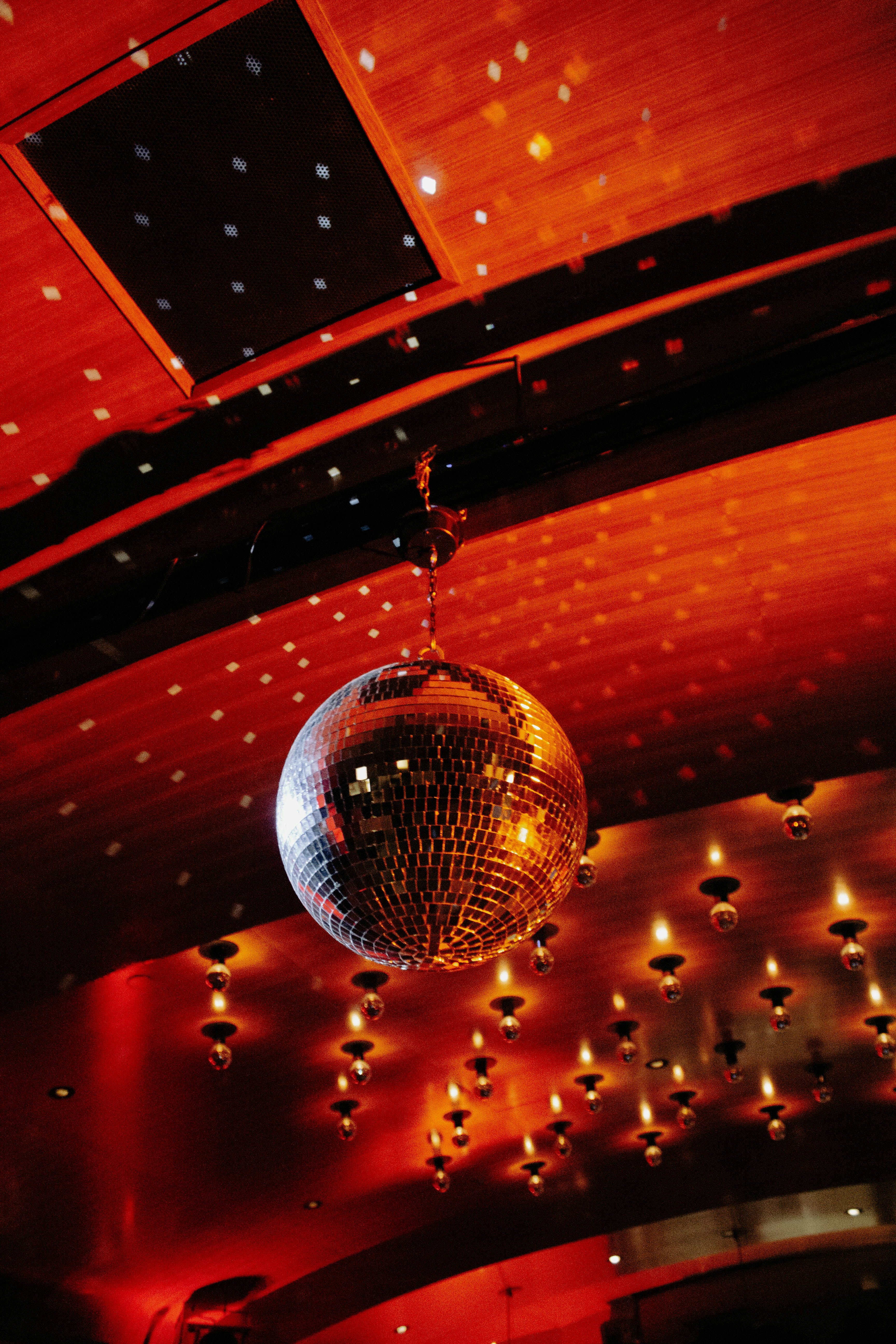 Disco ball reflecting light across a dimly lit ceiling with warm tones.