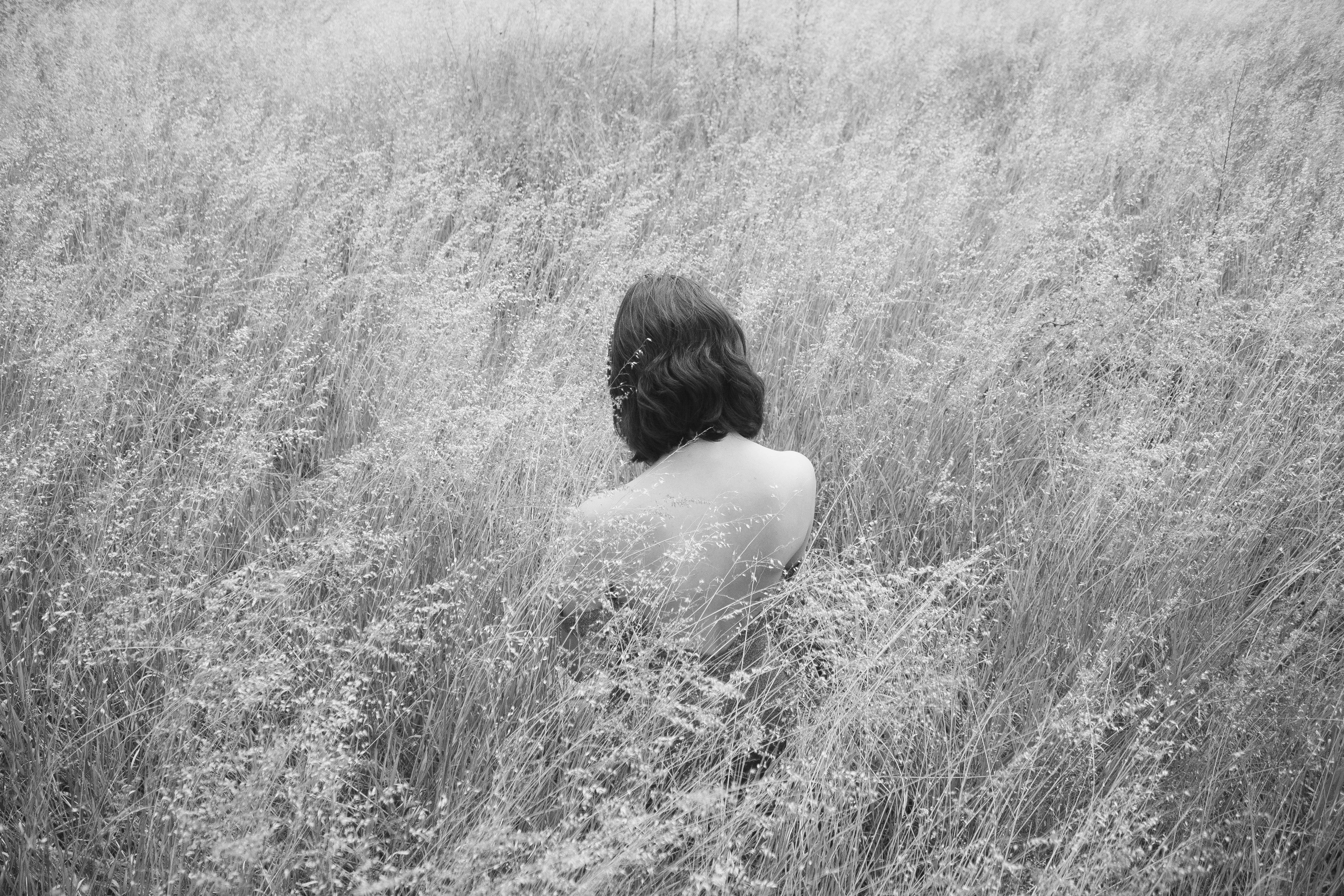 Woman walks through a field of tall grass.