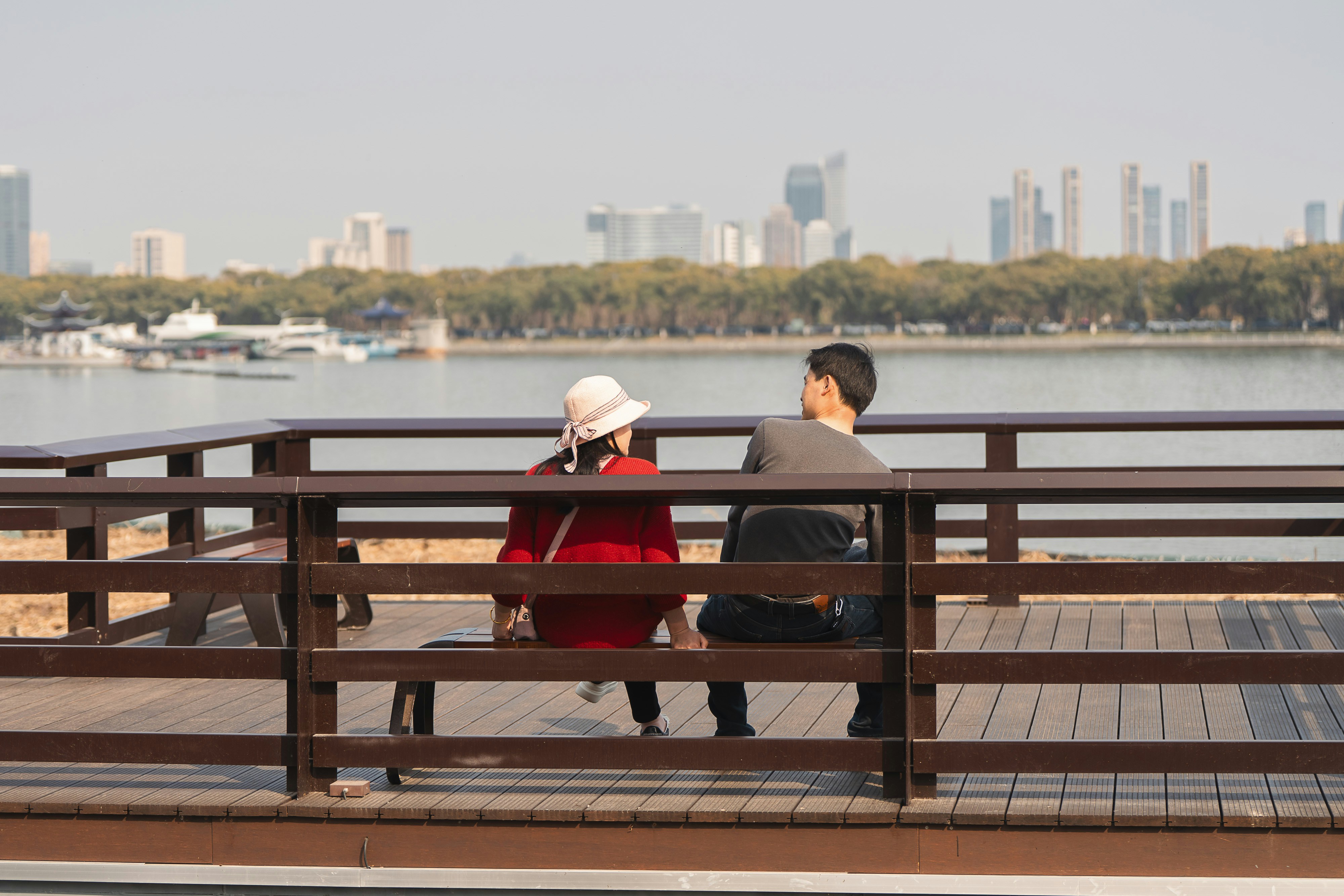 A couple sits by the water, overlooking the city. photo – Free Woman ...