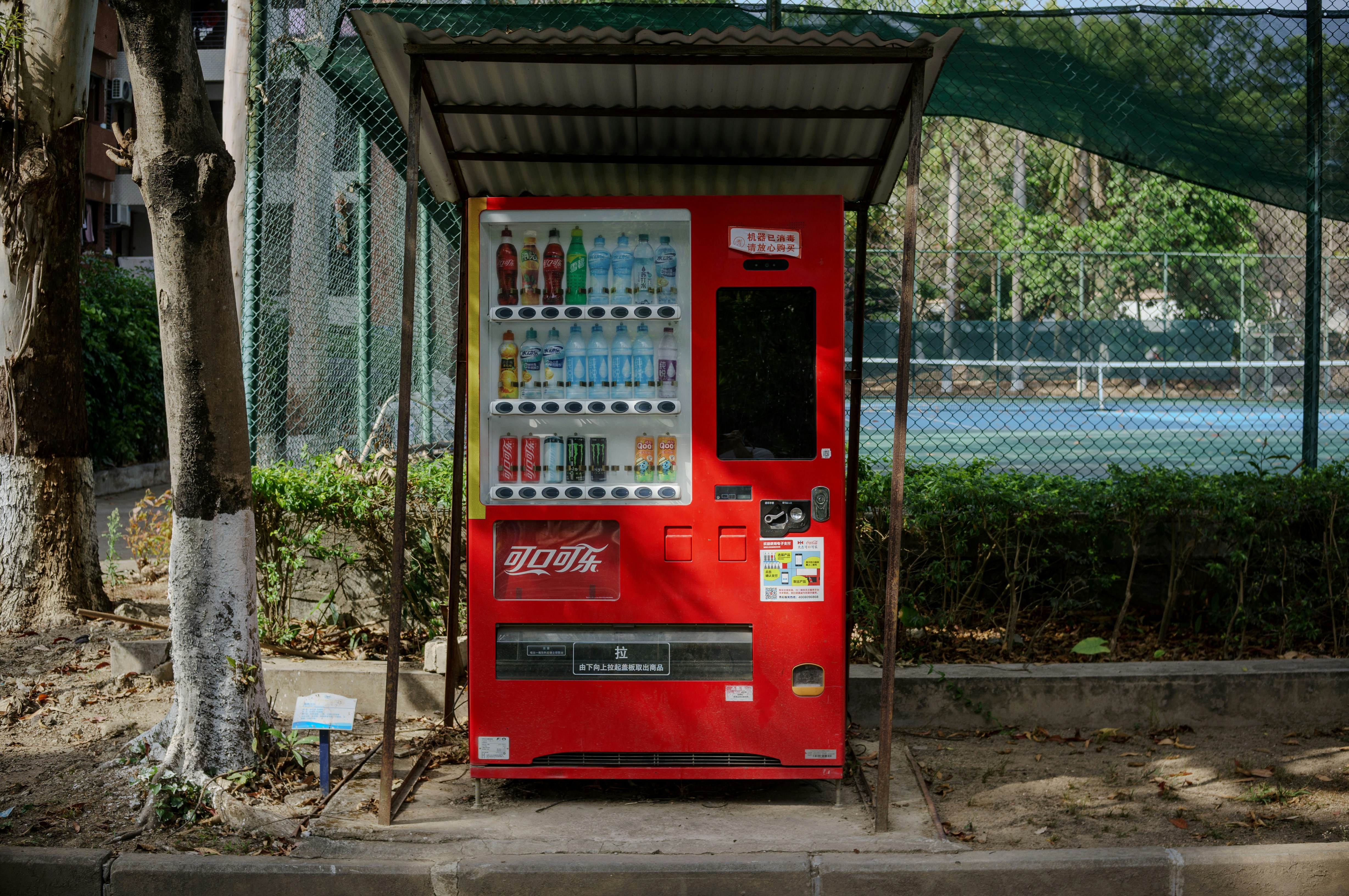 A red vending machine stands under a canopy. photo – Free Machine Image ...