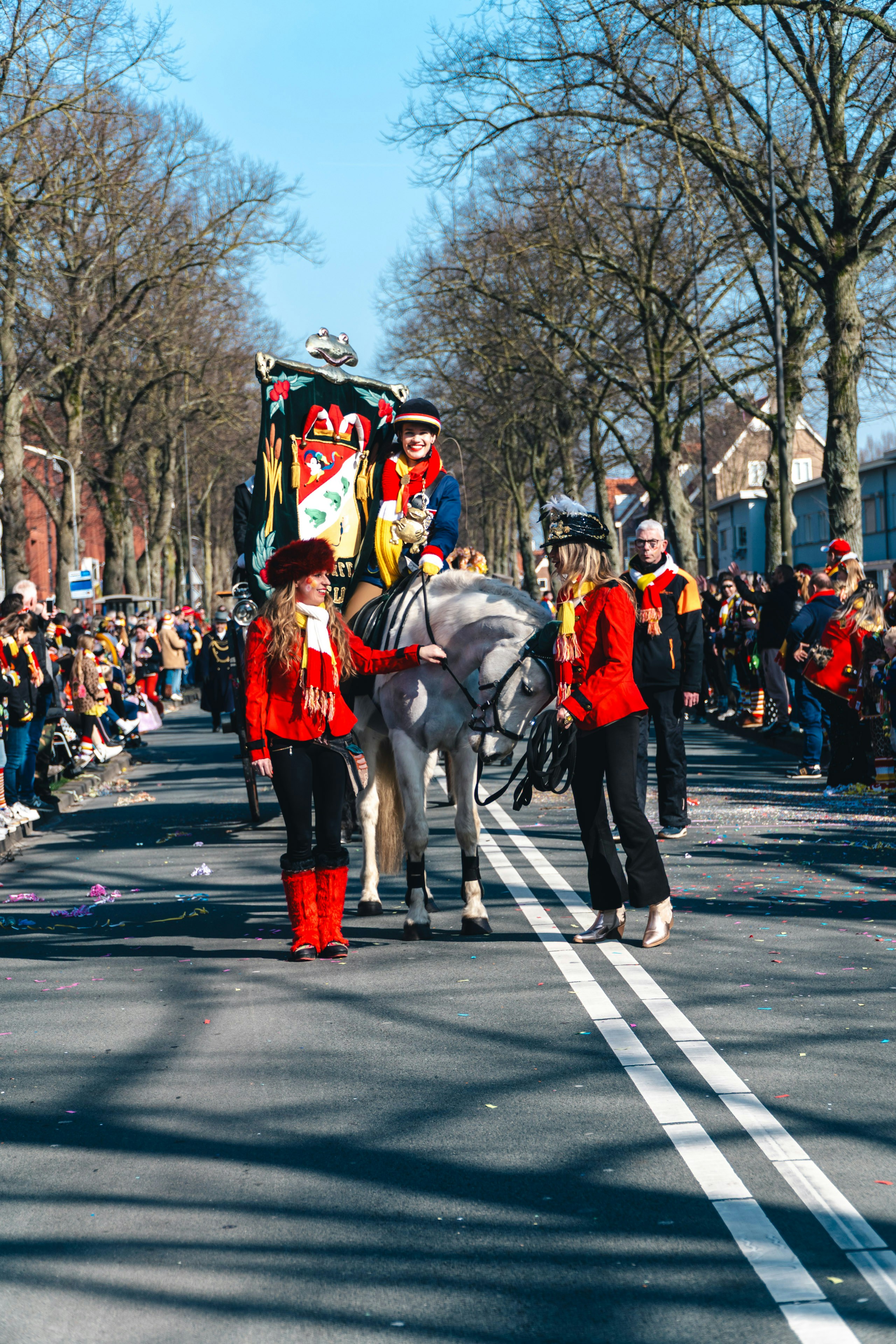 Flag-Bearing Rider on a Dappled Gray Horse Leads a Festive Street Parade