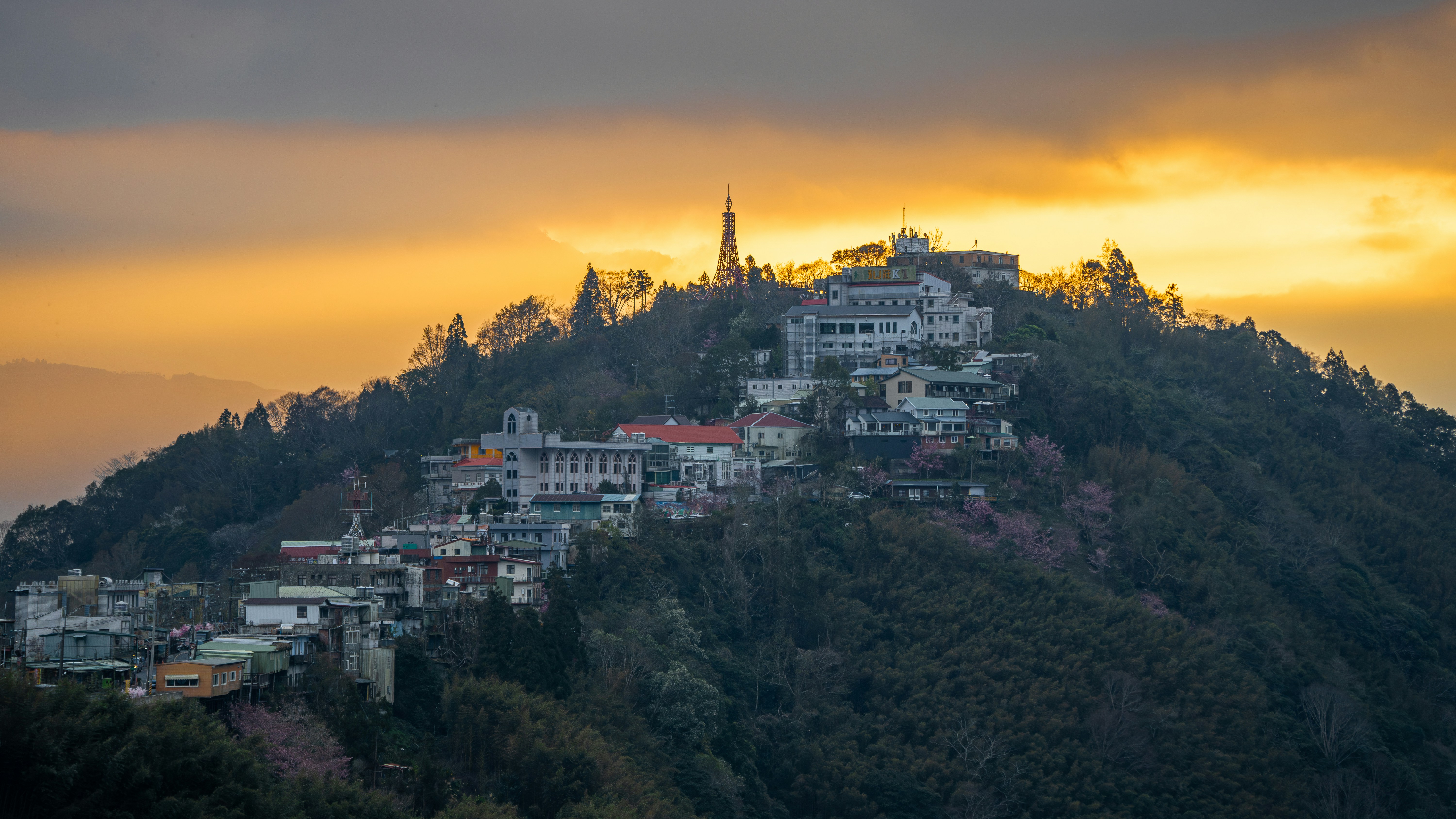 Village on a hill with a tower silhouetted against a vibrant sunset sky.