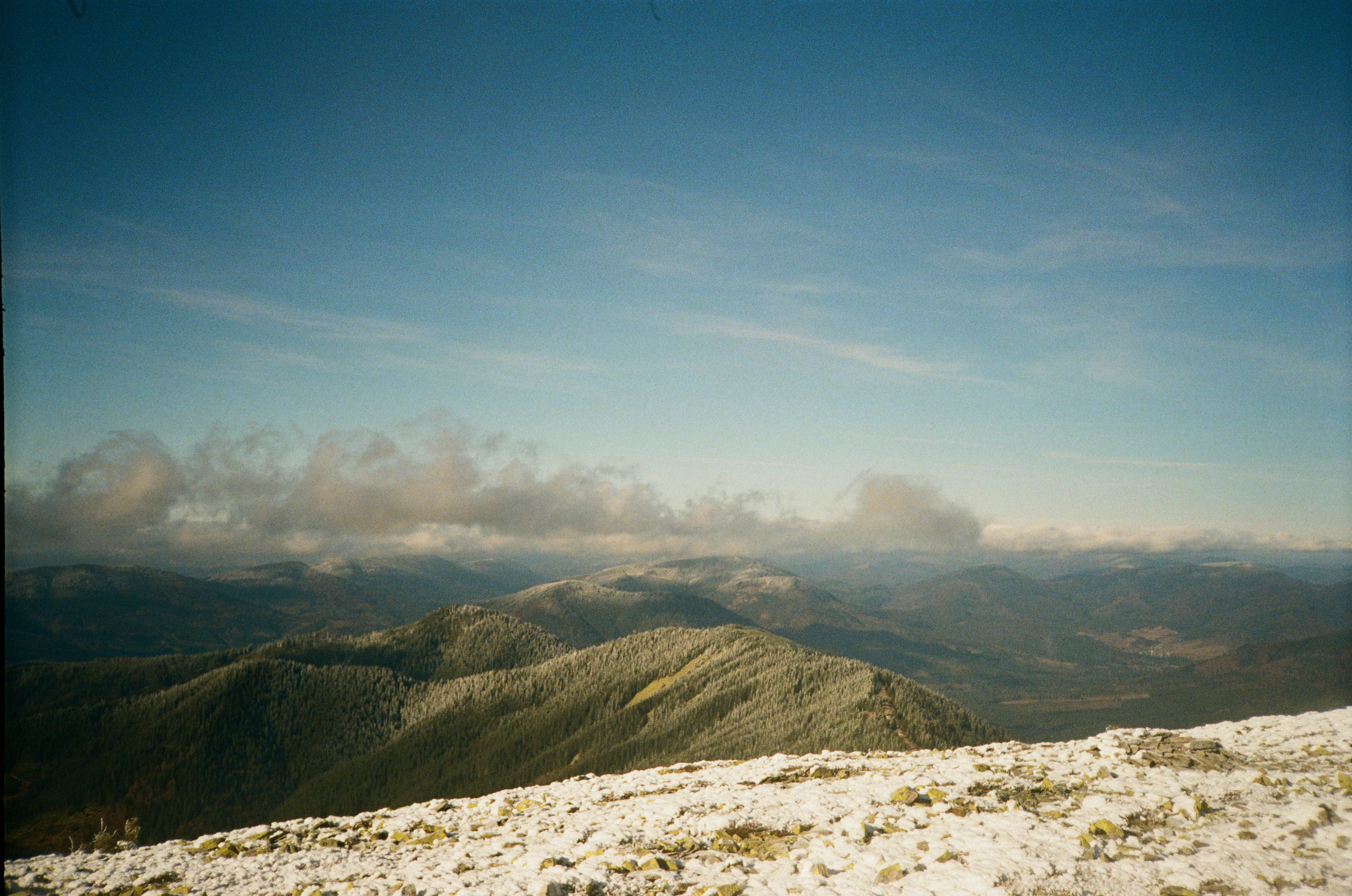 Snow-dusted mountains under a blue sky with scattered clouds.