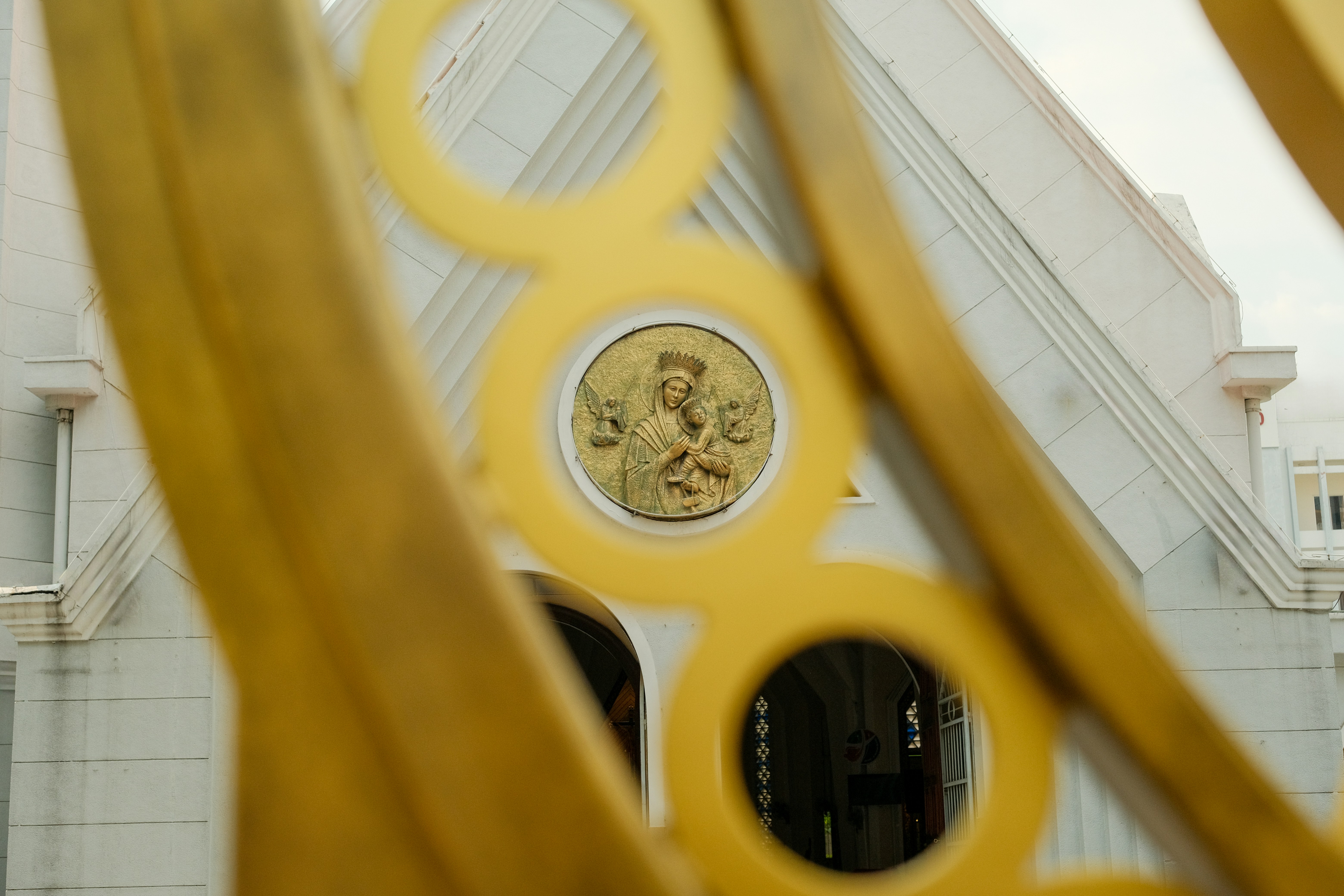 Golden circular frame highlighting a religious relief on a building facade.